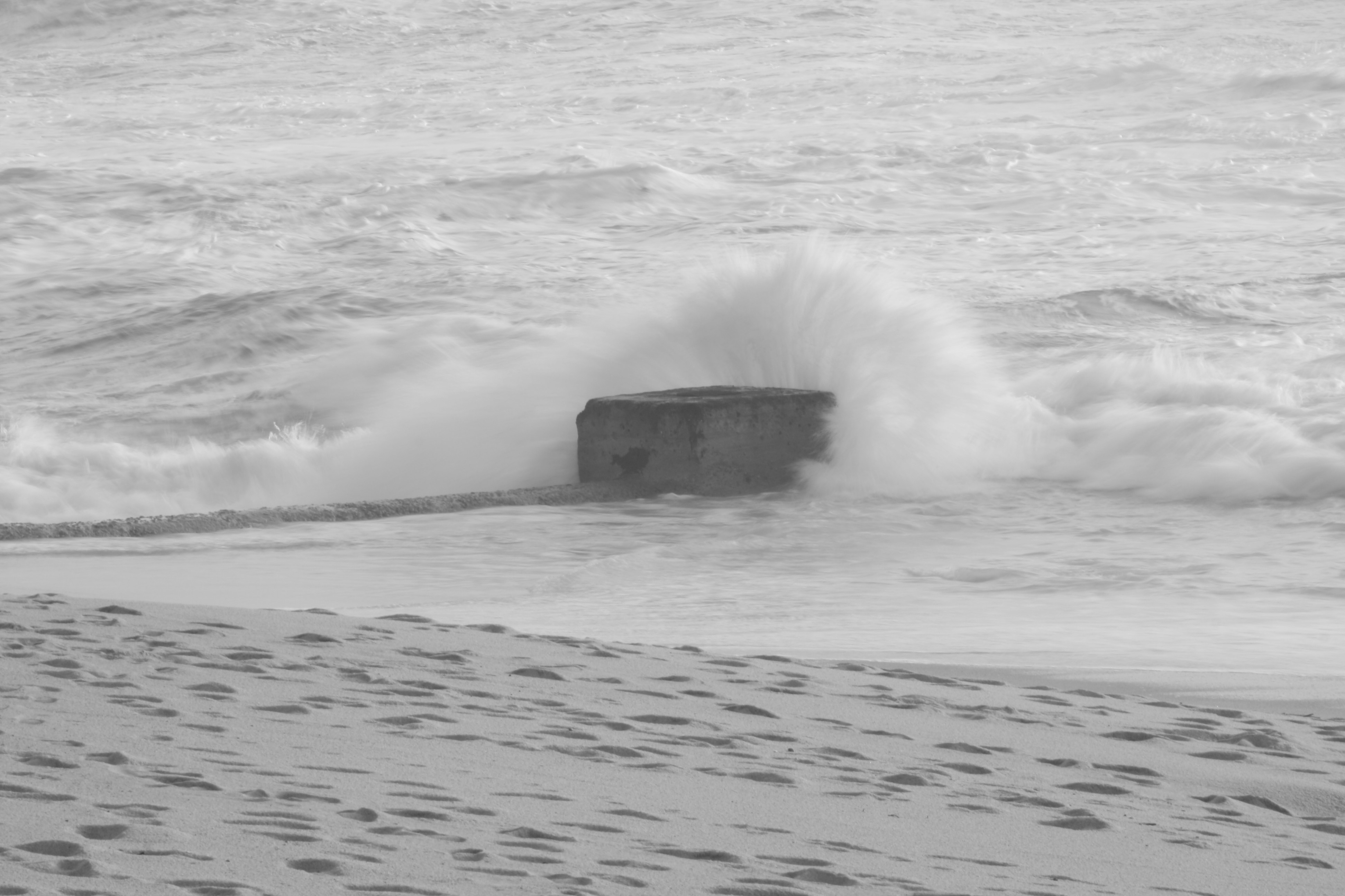 Une photo en noir et blanc de vagues s’écrasant sur un rocher photo ...