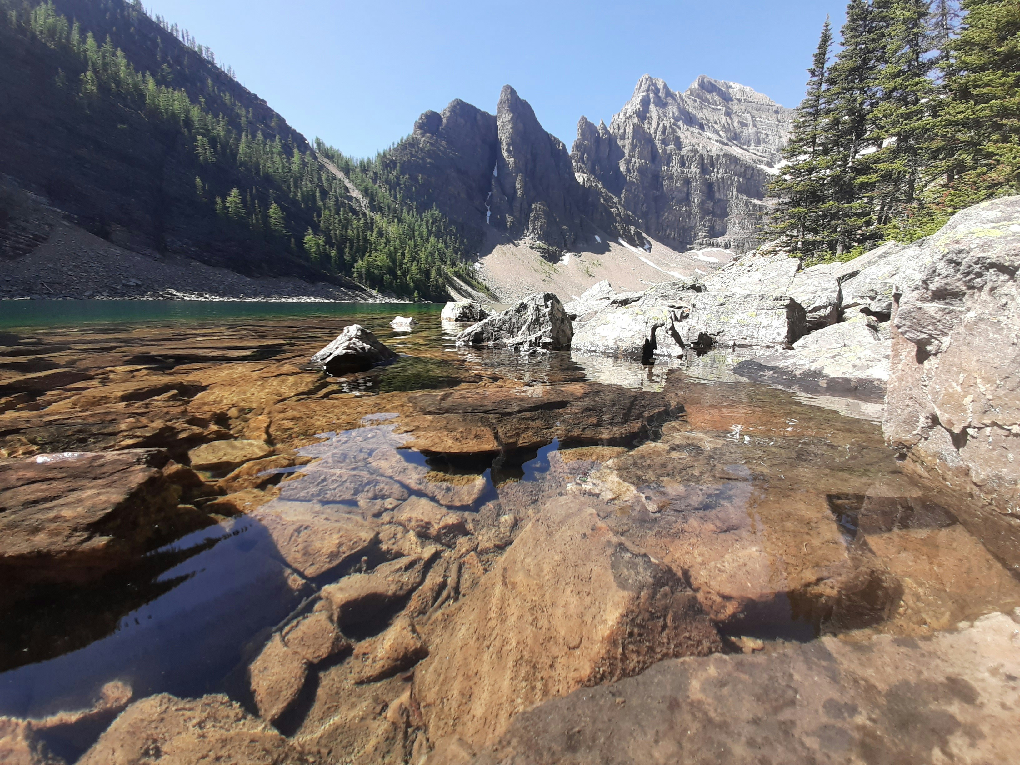 A mountain lake surrounded by rocks and trees photo – Free Alberta ...