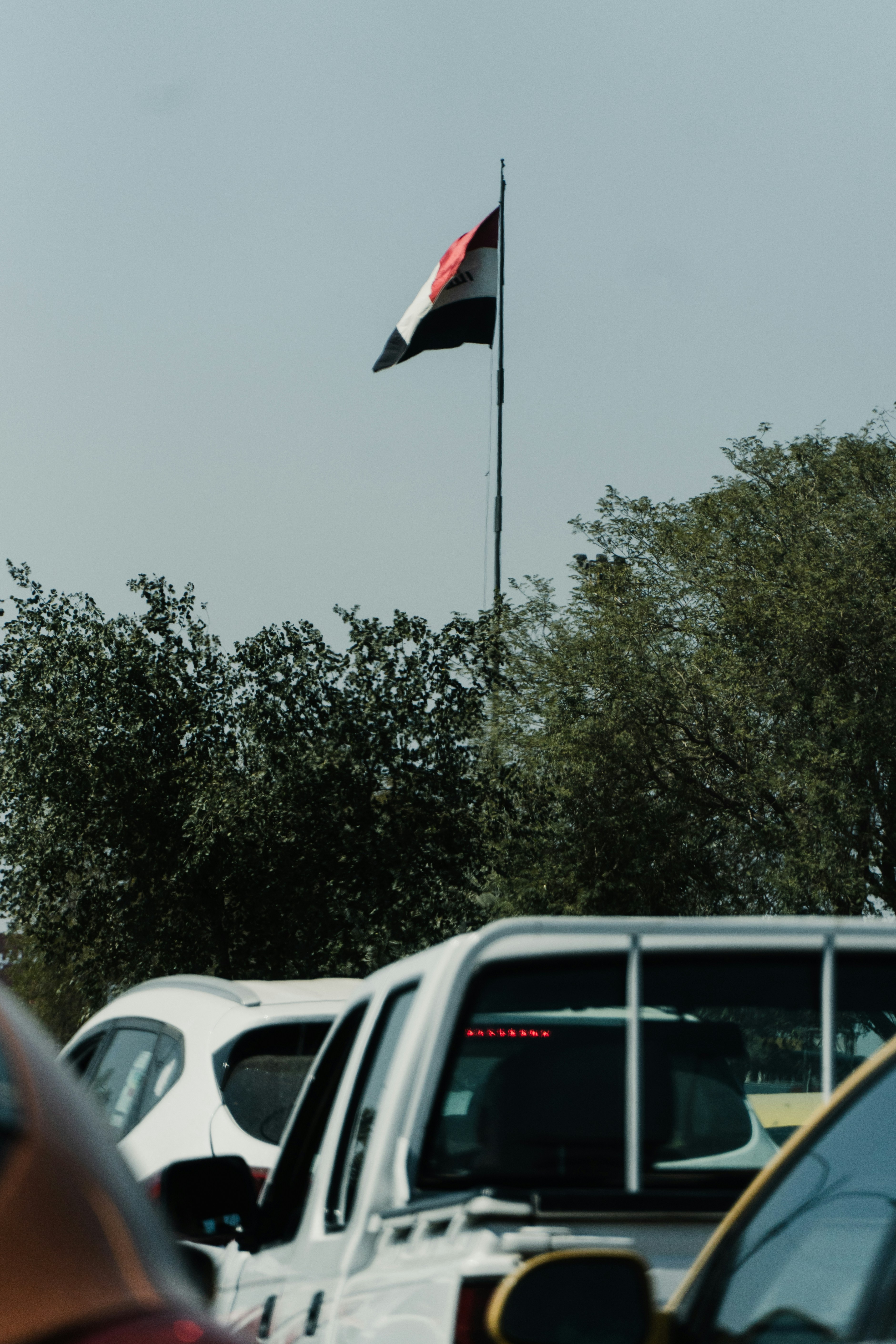 a canadian flag flying over a parking lot full of cars