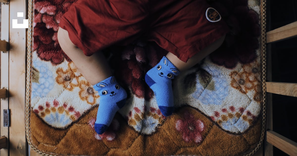 파란 양말을 신고 침대에 누워 있는 작은 아이 사진 Unsplash의 무료 바탕가스 이미지