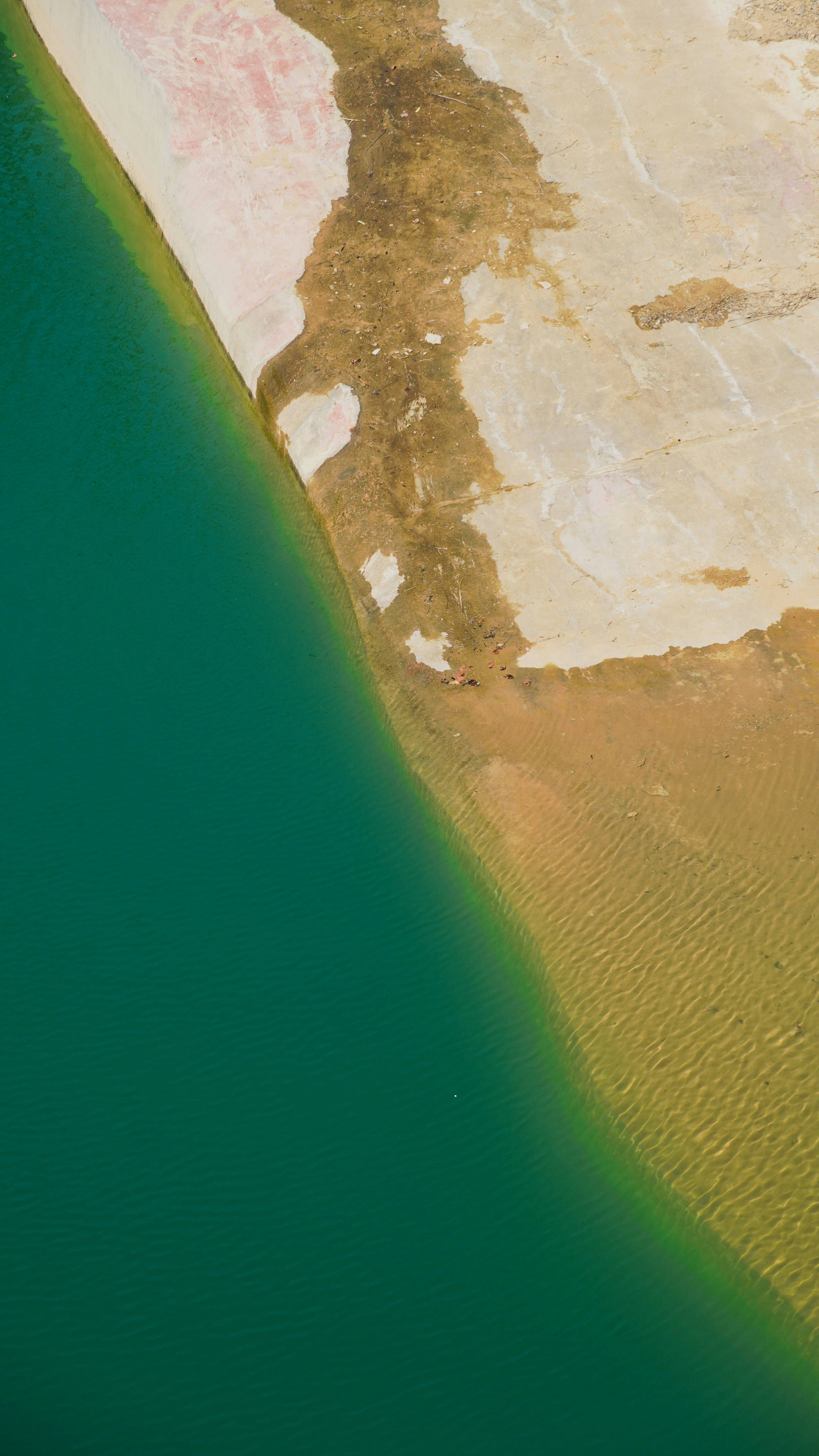 Aerial view showcasing the transition between vibrant turquoise water and the textured shoreline, highlighting nature's delicate balance.