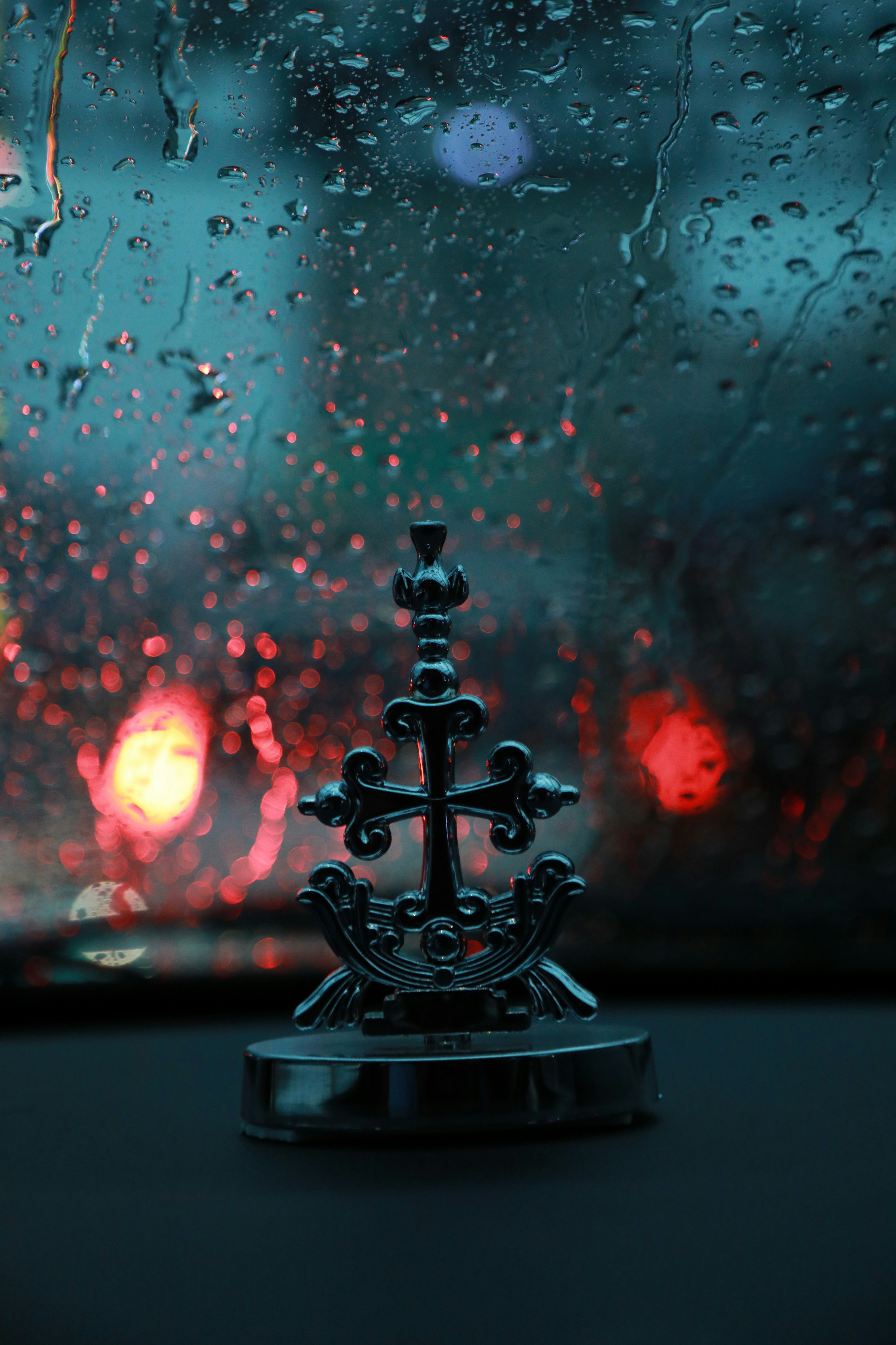 a rain soaked window with a small black anchor on it