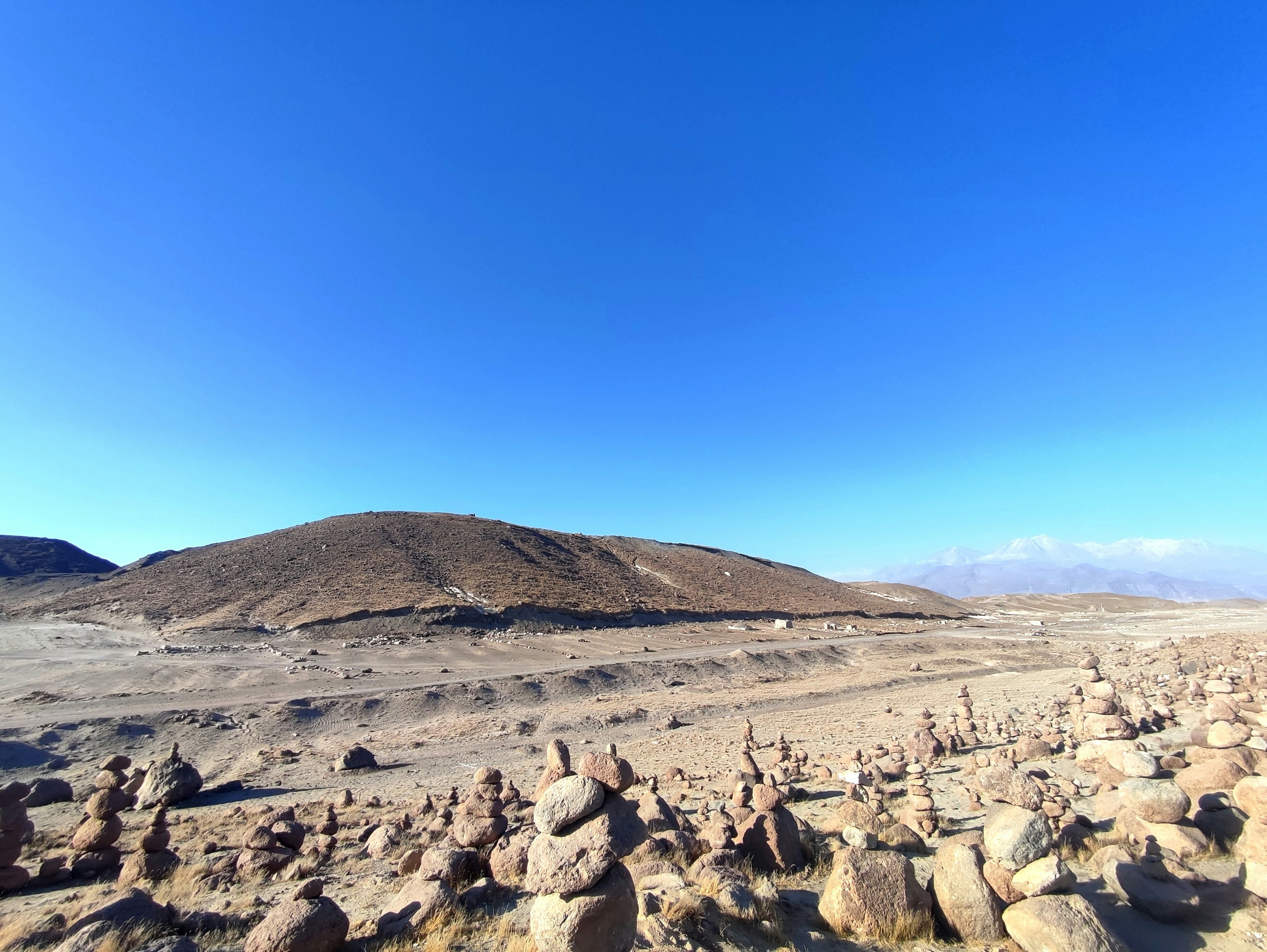 Rock formations scattered across an arid desert landscape beneath a clear blue sky.