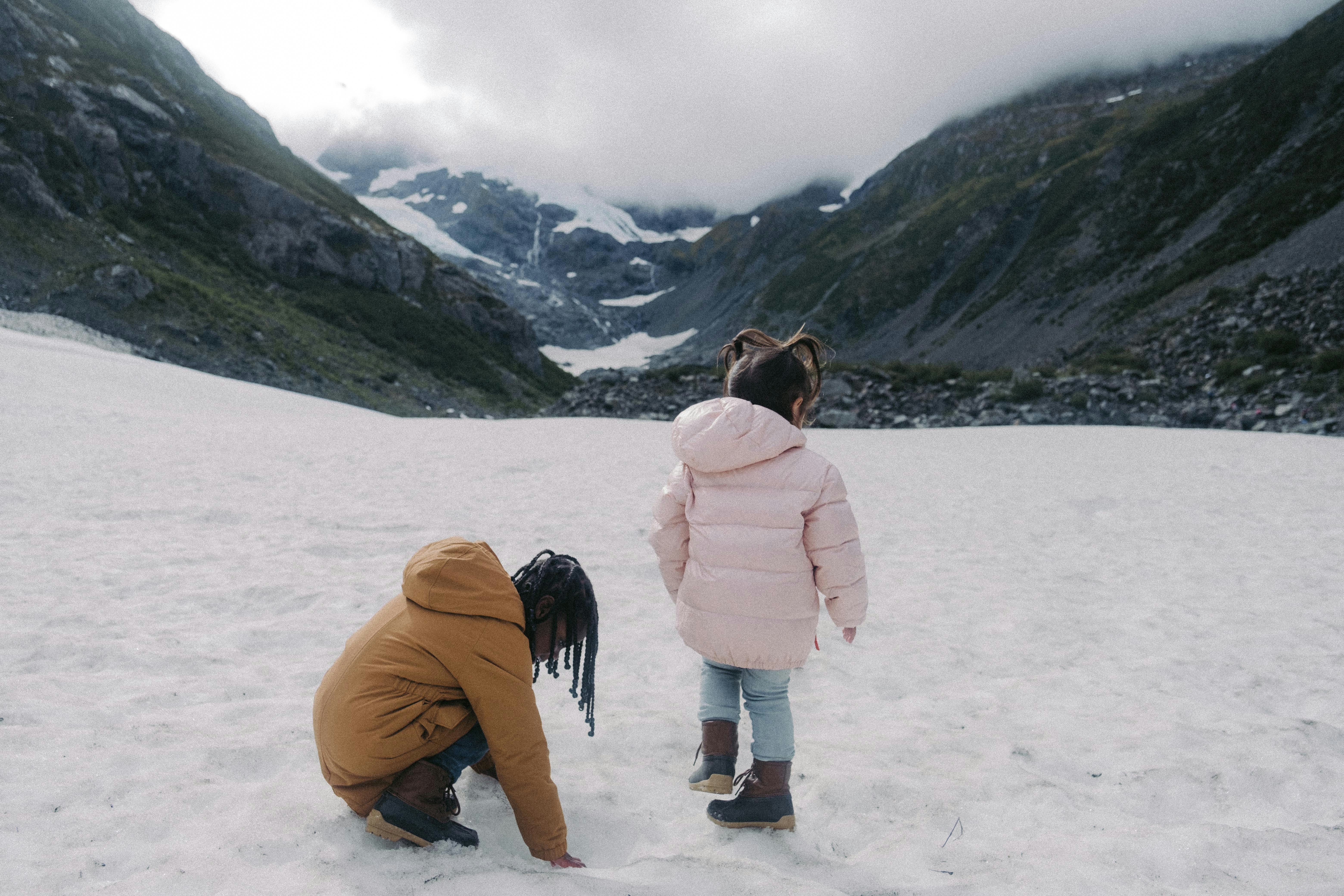 Two Children Explore a Snowy Alpine Basin