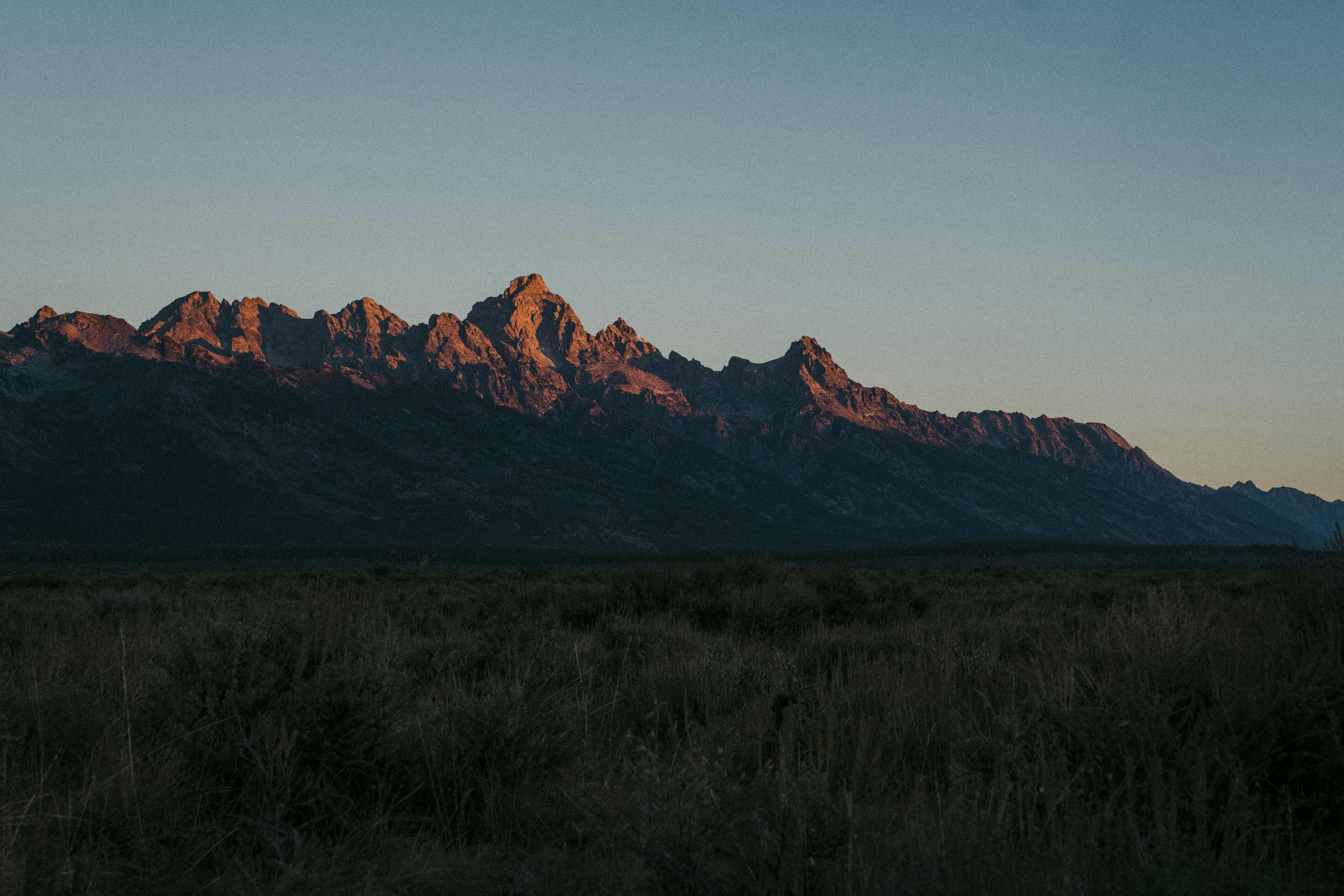 A large mountain range in the distance with grass in the foreground ...