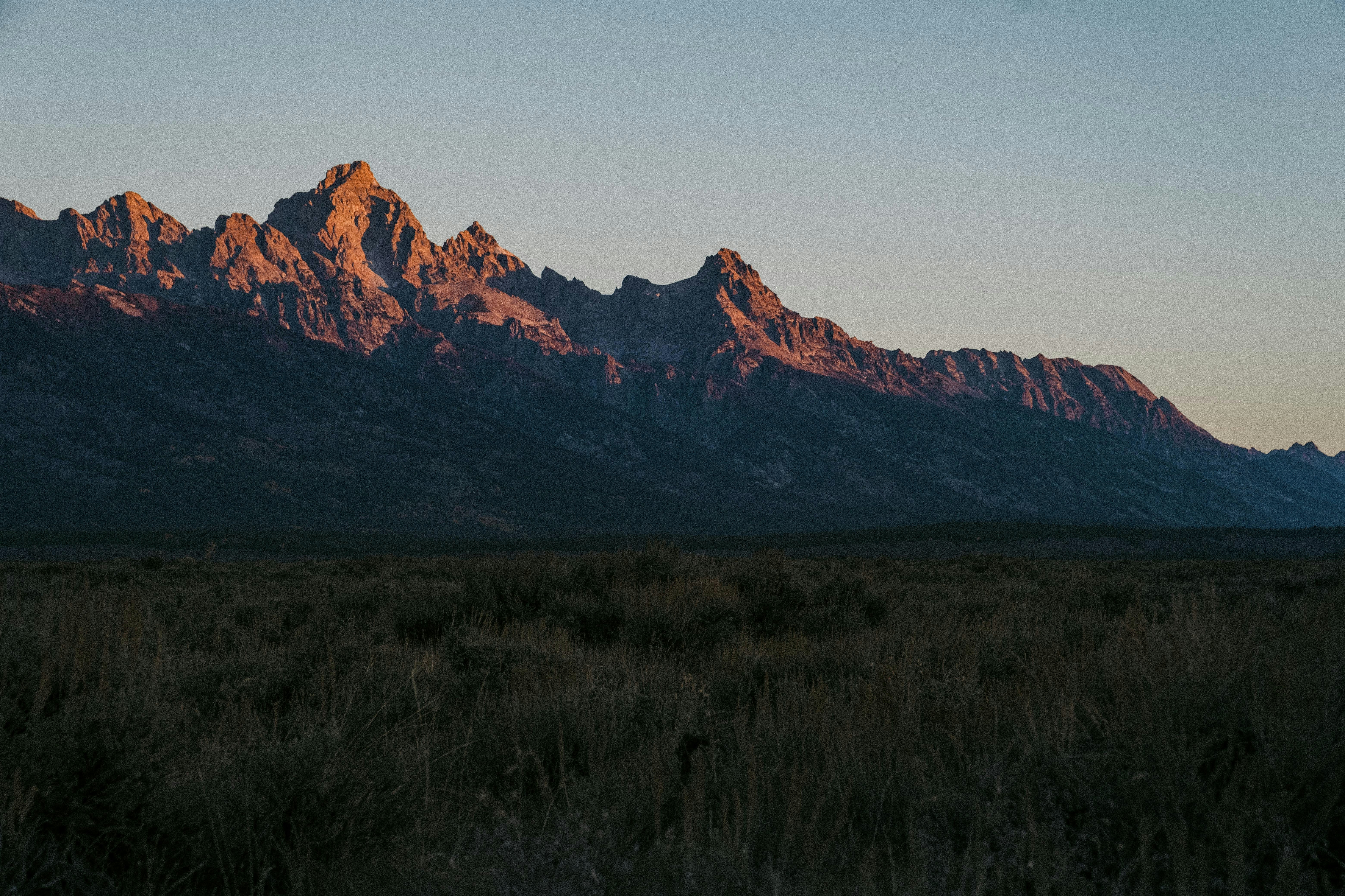 A large mountain range in the distance with grass in the foreground ...