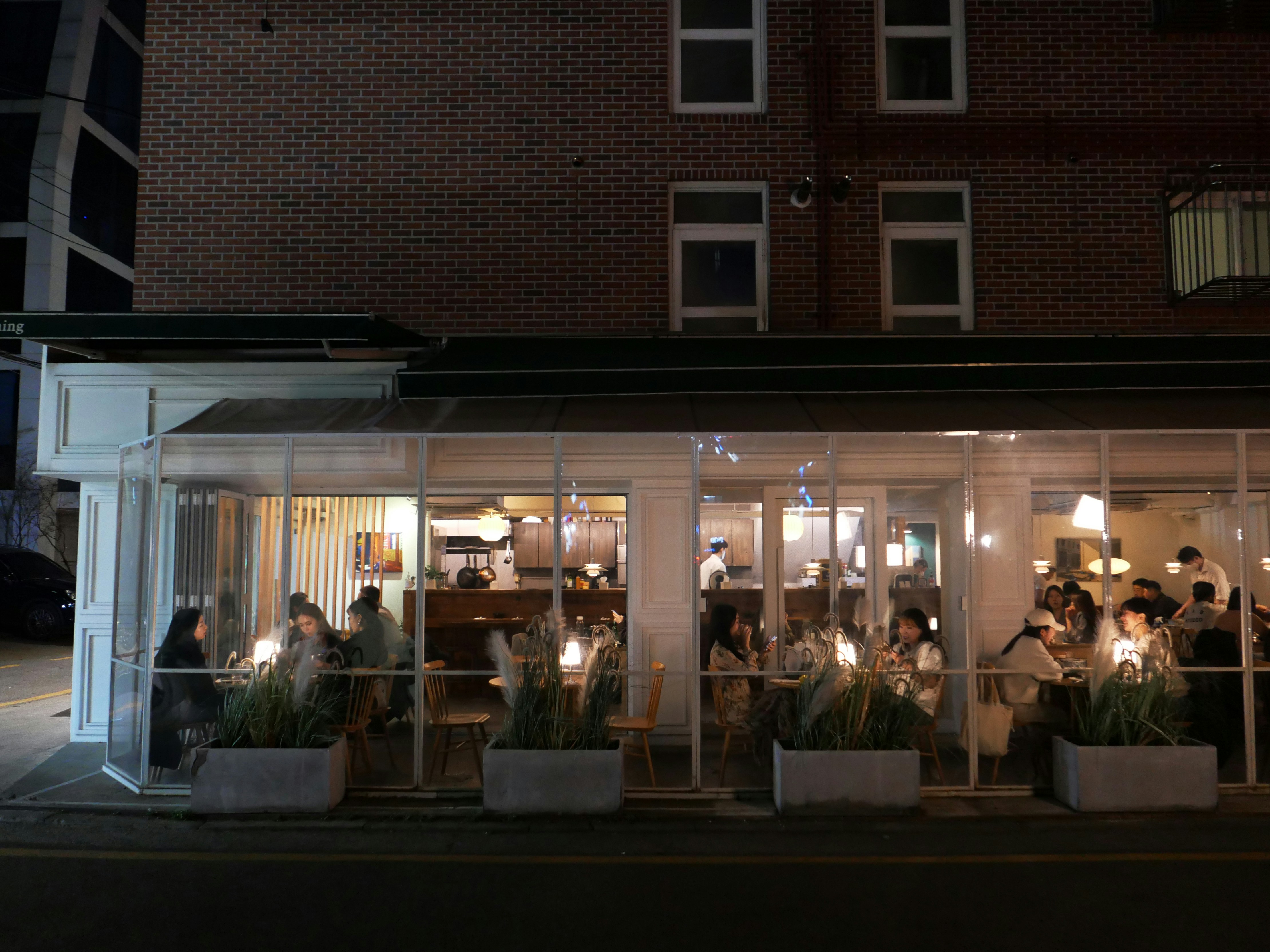Glass-walled Café at Dusk: Warm Conversation Inside a City Street