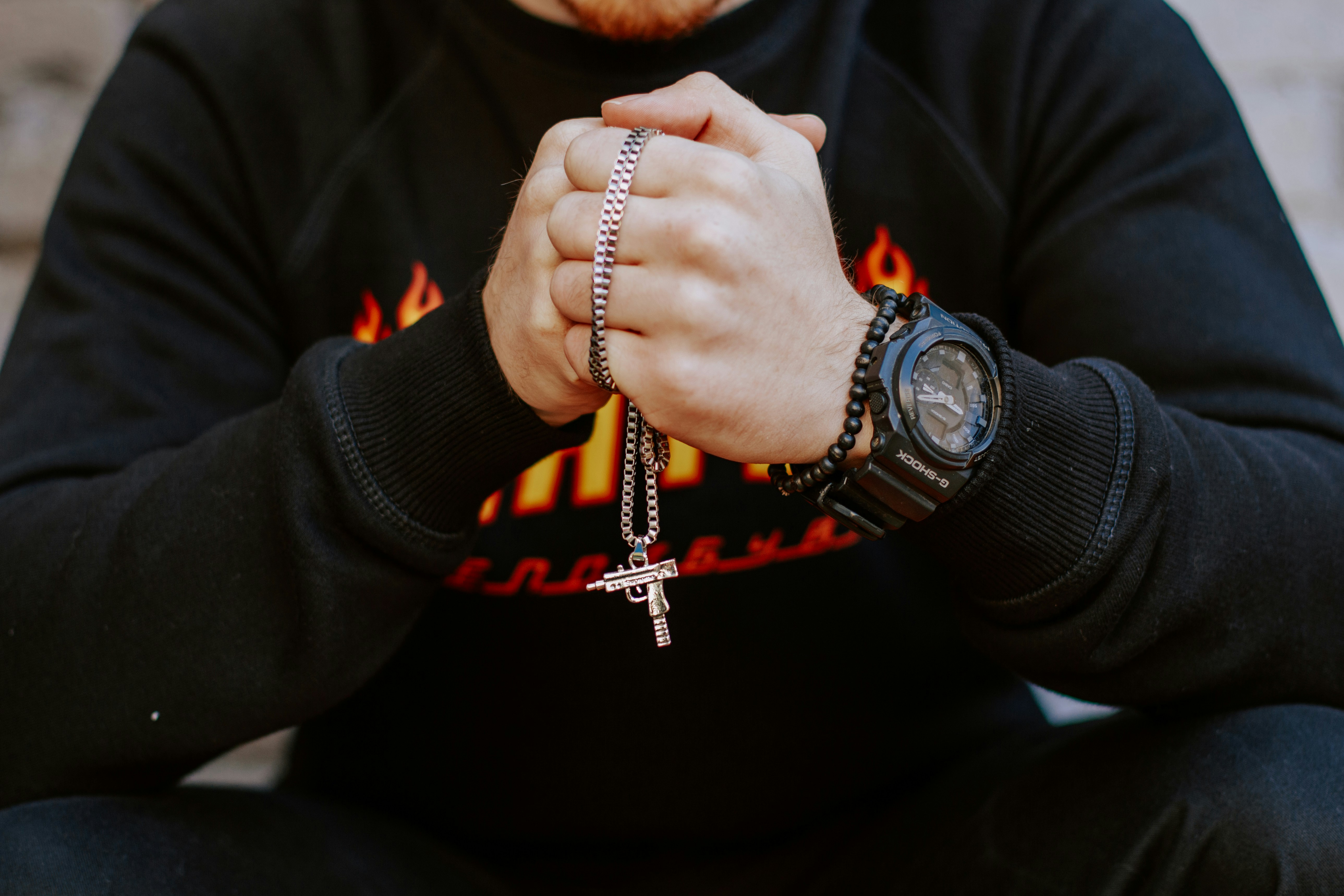 Cross Necklace Grasp: A Quiet Moment in Noir Streetwear