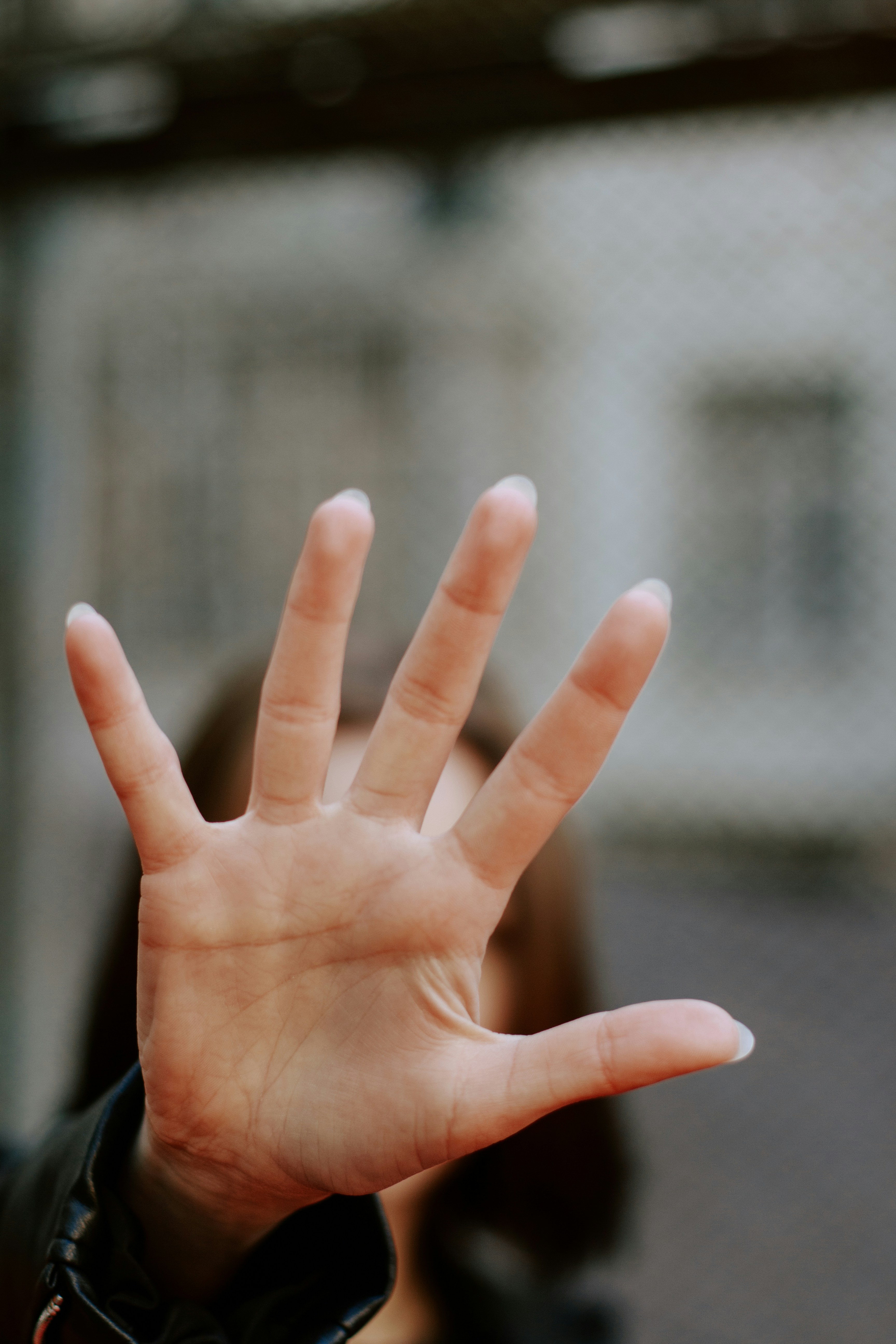 Open hand raised in a stop gesture against a blurred urban backdrop.