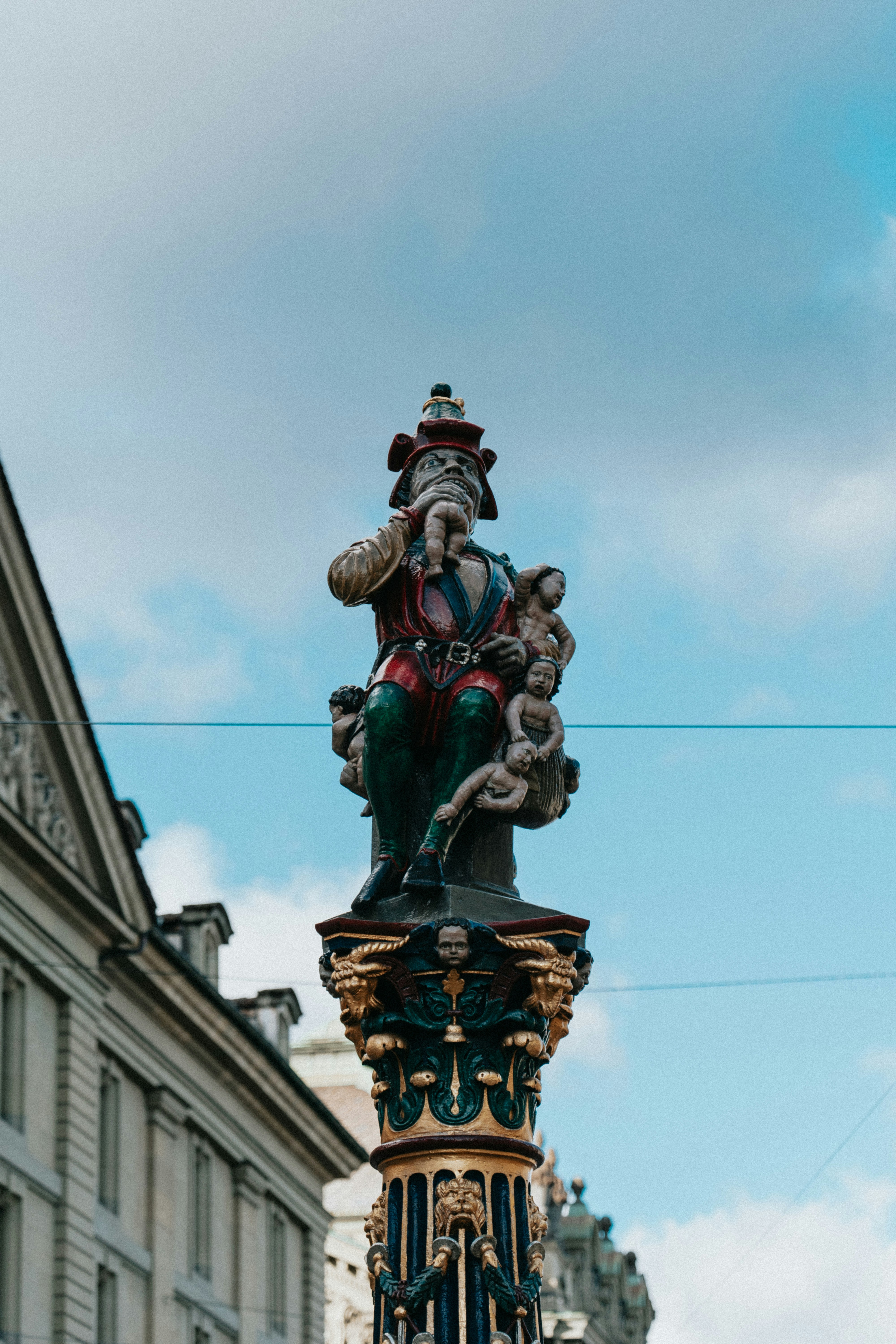 Guardians on the Column: A towering statue crowned by cherubs overlooking a quiet European street