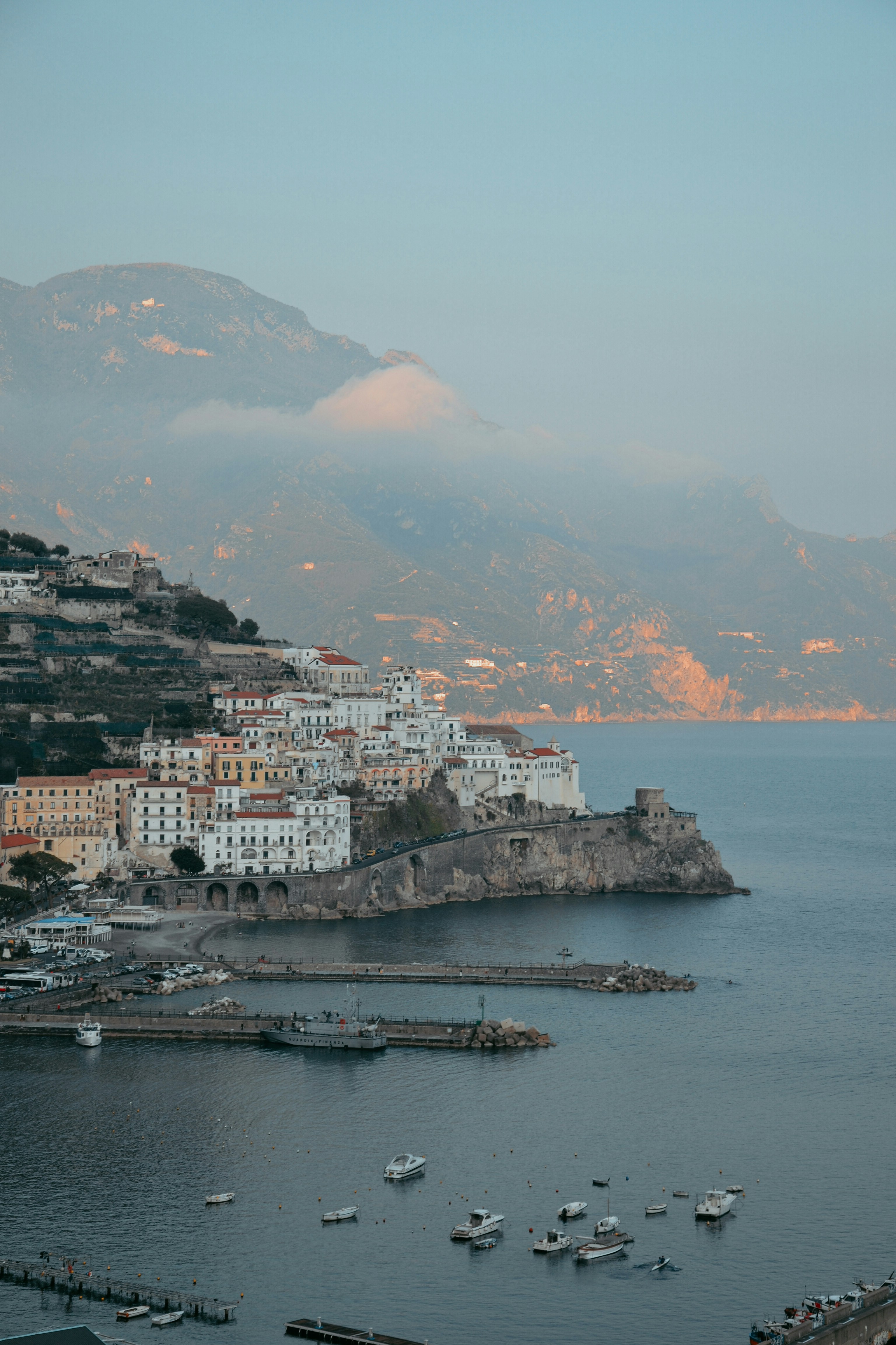 Charming coastal village nestled against the cliffs, showcasing whitewashed buildings and serene waters. The scene captures the essence of Mediterranean tranquility.
