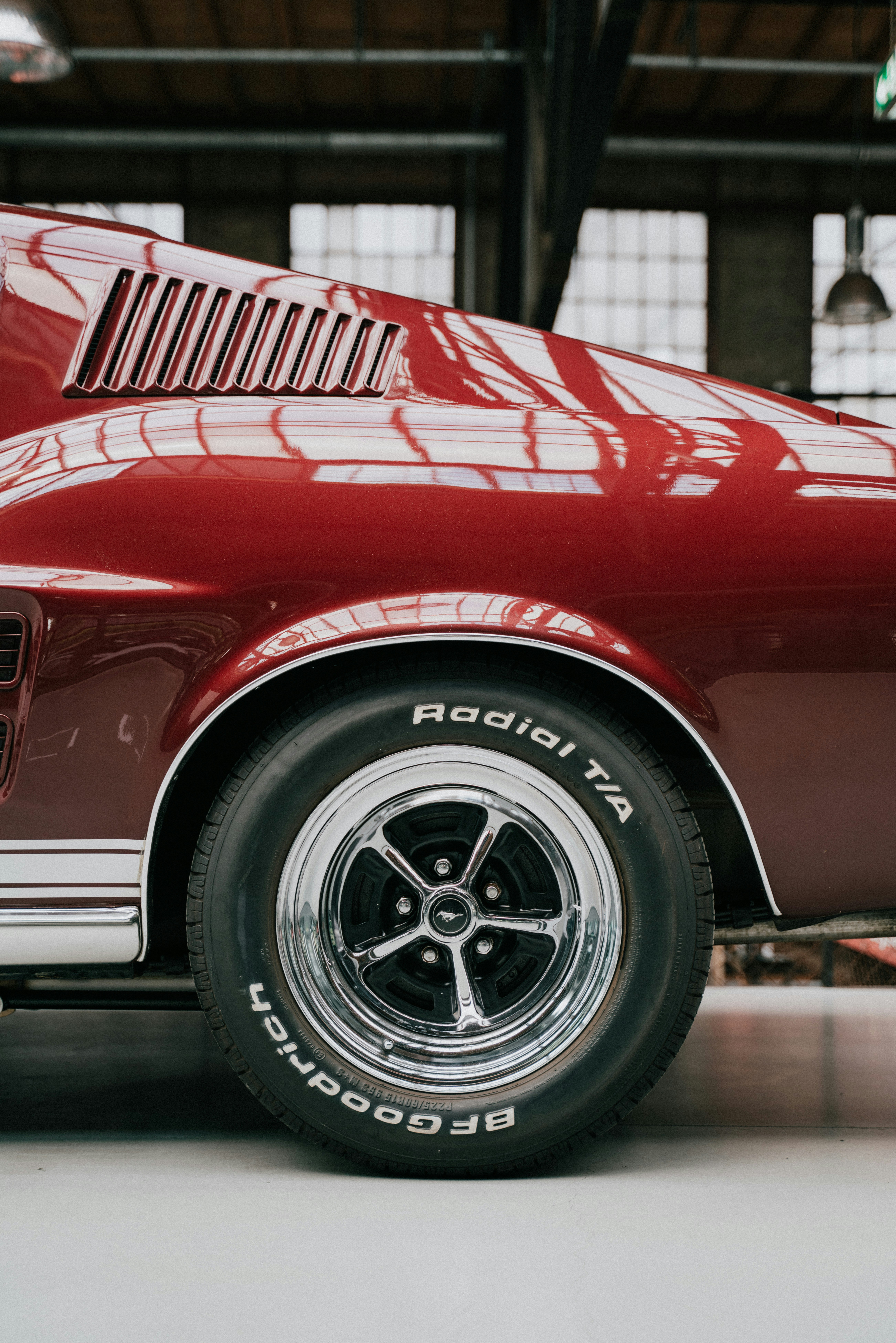 Chromed Rhythm: Close-Up of a Red Muscle Car's Wheel under Industrial Light