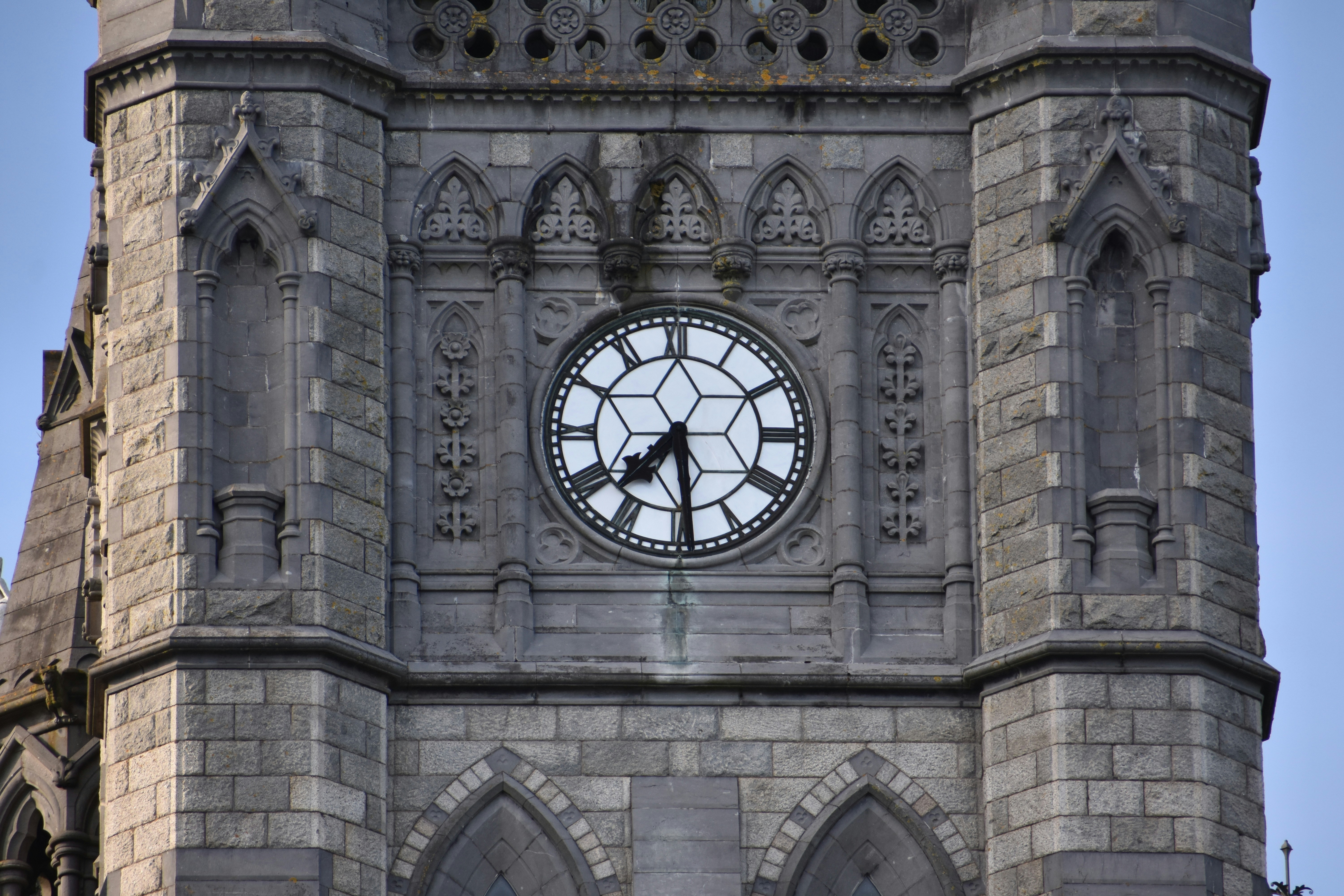 Intricate stone carvings adorn the clock tower, featuring a large, fractured clock face that tells the passage of time.