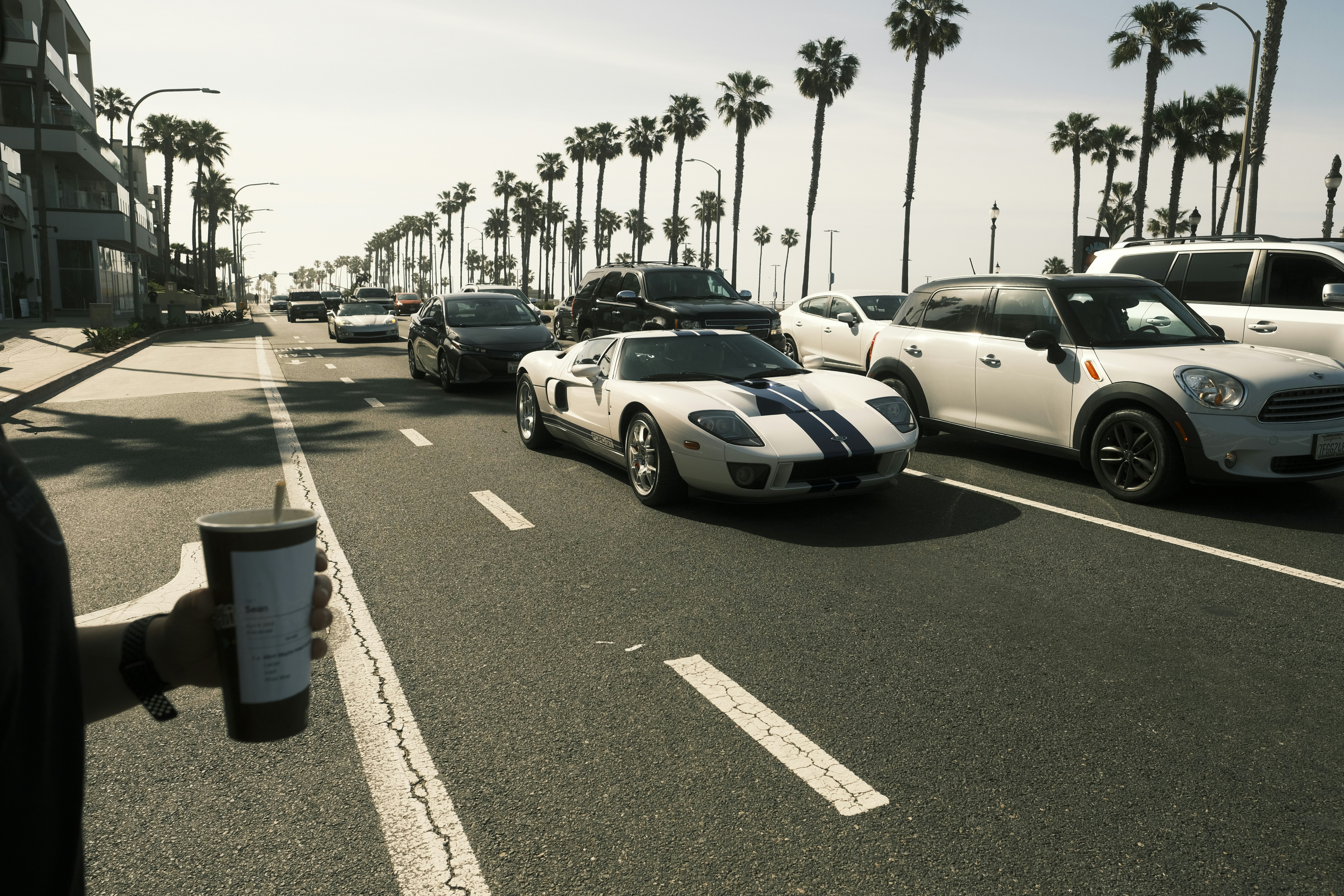 Sunlit Coastal Parade: A Convertible Converges on Oceanfront Traffic