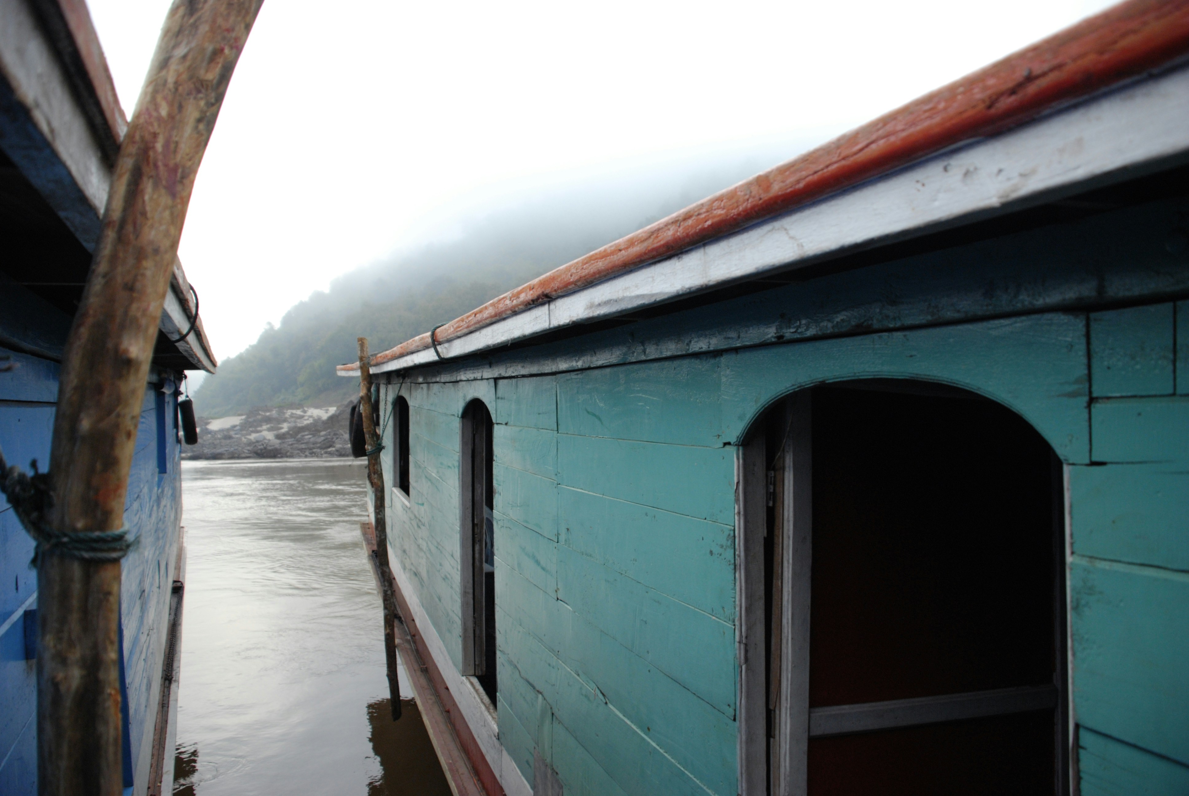 Teal Hulls in the Mist: A Narrow Passage Between Boats