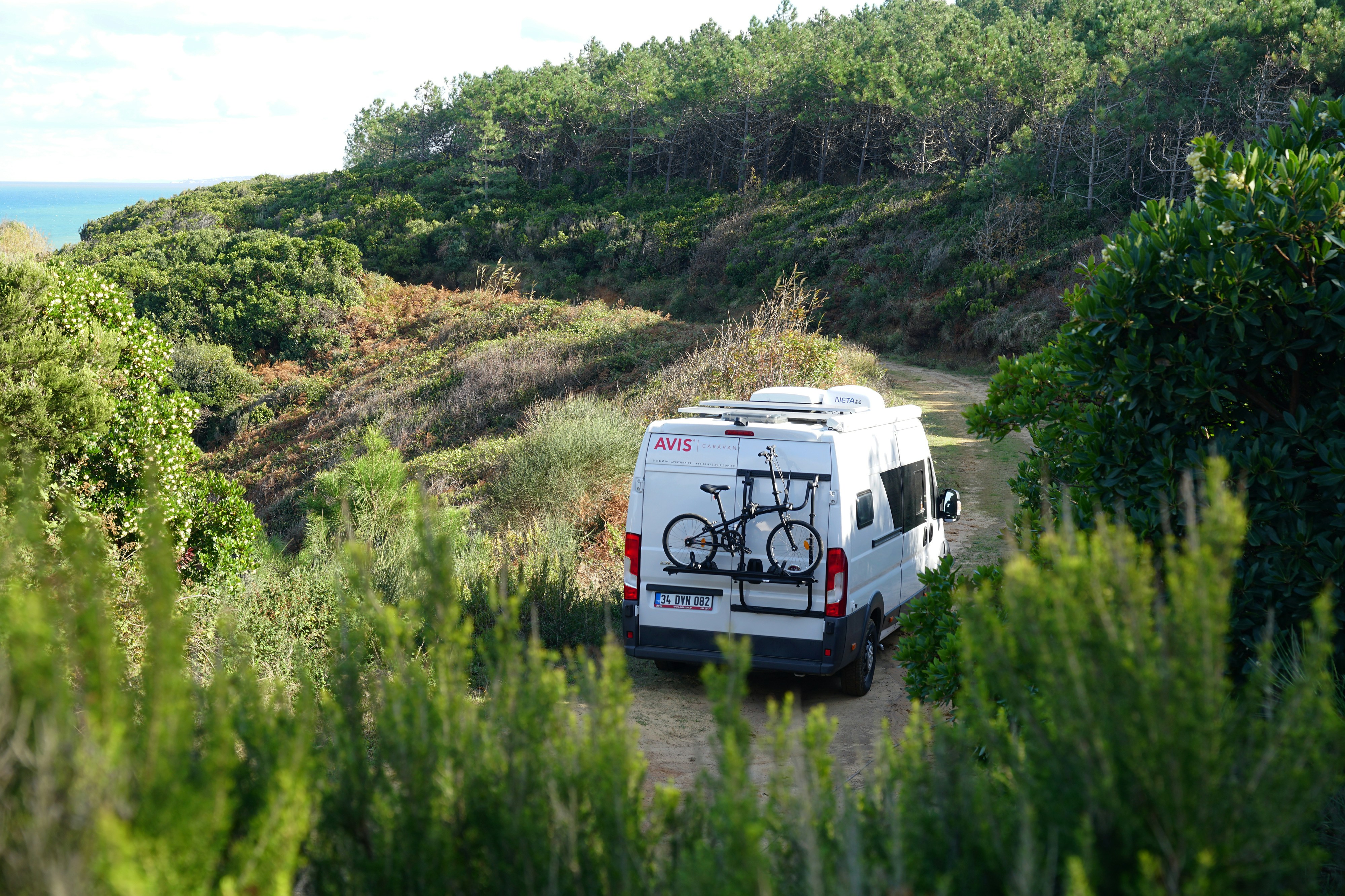 Kampbros.com | a van parked on a dirt road with a bike mounted to the back of it