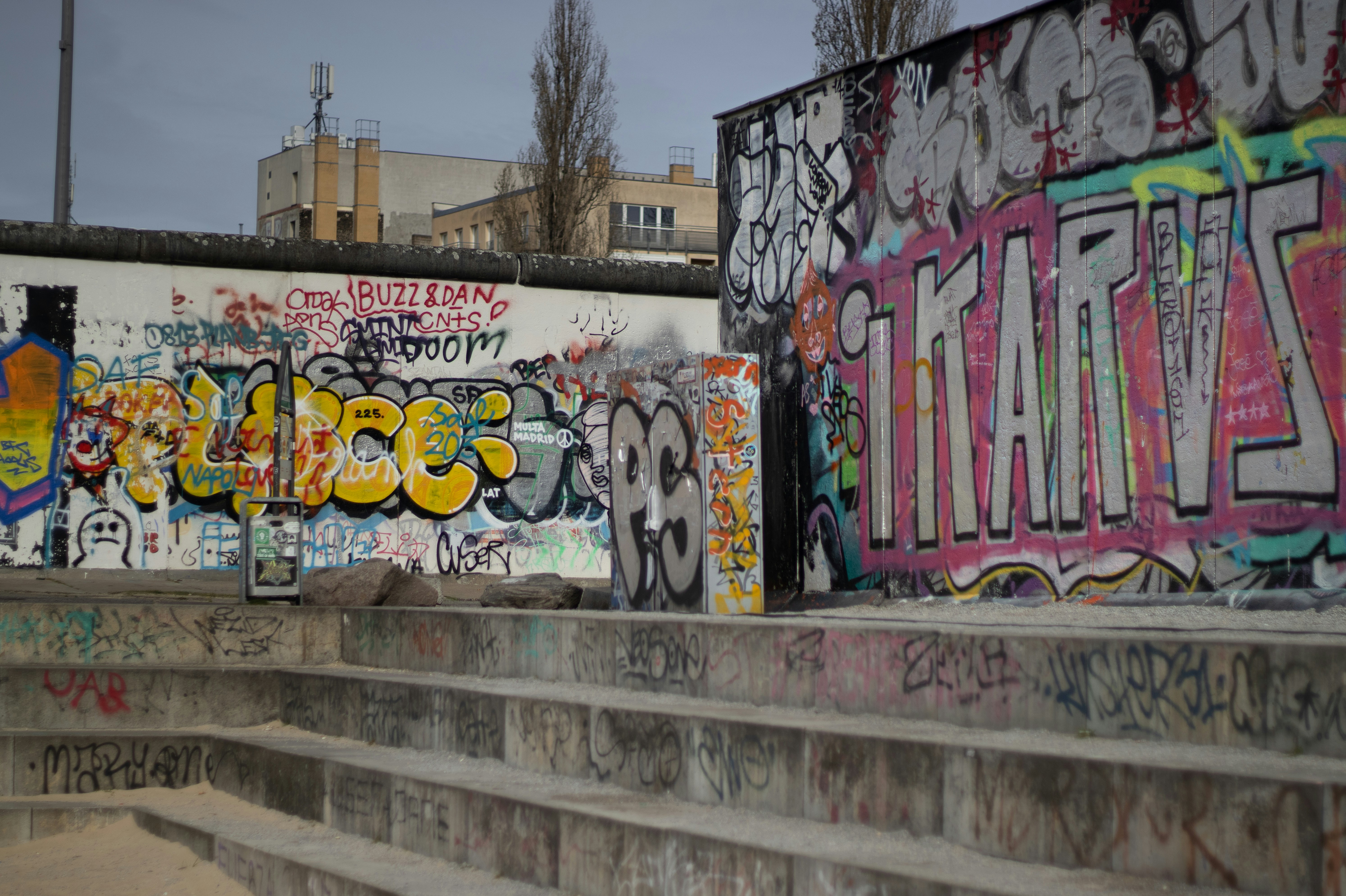 Vibrant street art covering a concrete wall, showcasing a mix of graffiti styles and colors. The scene captures the essence of urban expression.