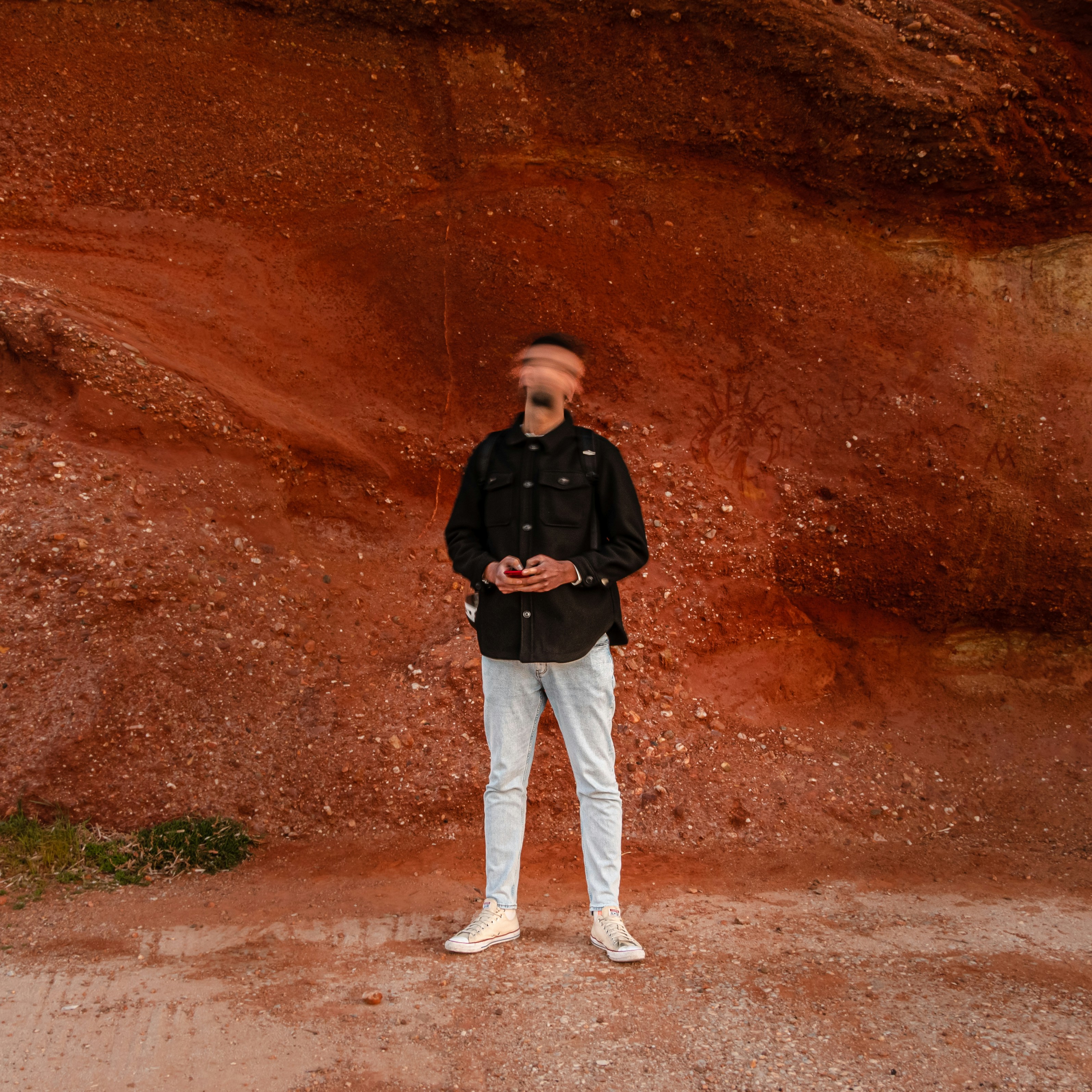 Red Rock Portrait: A Solo Explorer Stands Against a Rusted Cliff