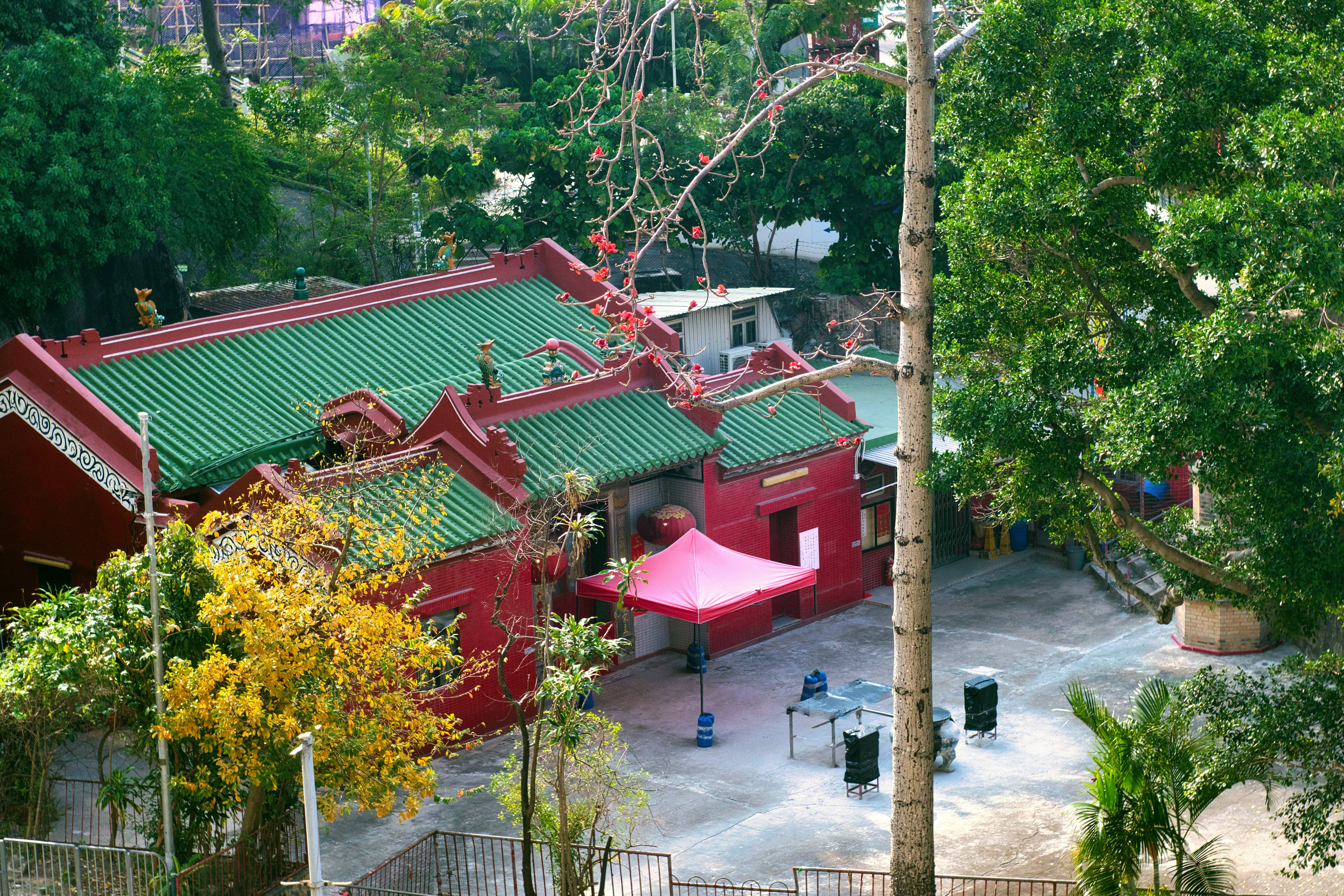 a red building with a green roof surrounded by trees
