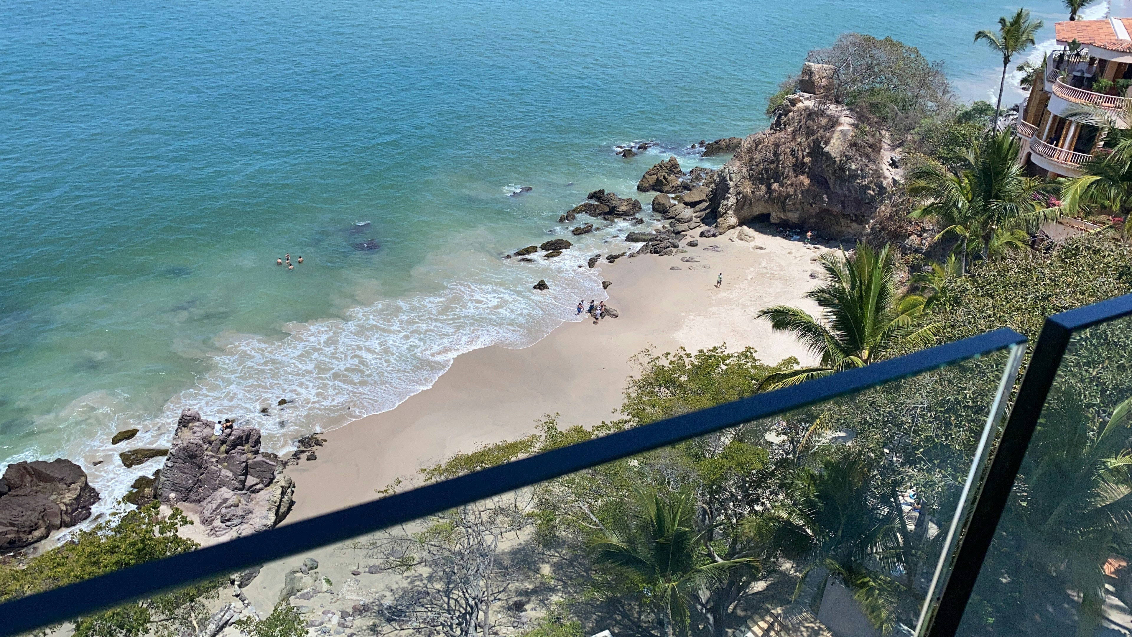 Balcony Vista: Turquoise Shore Framed by Rocks and Palms