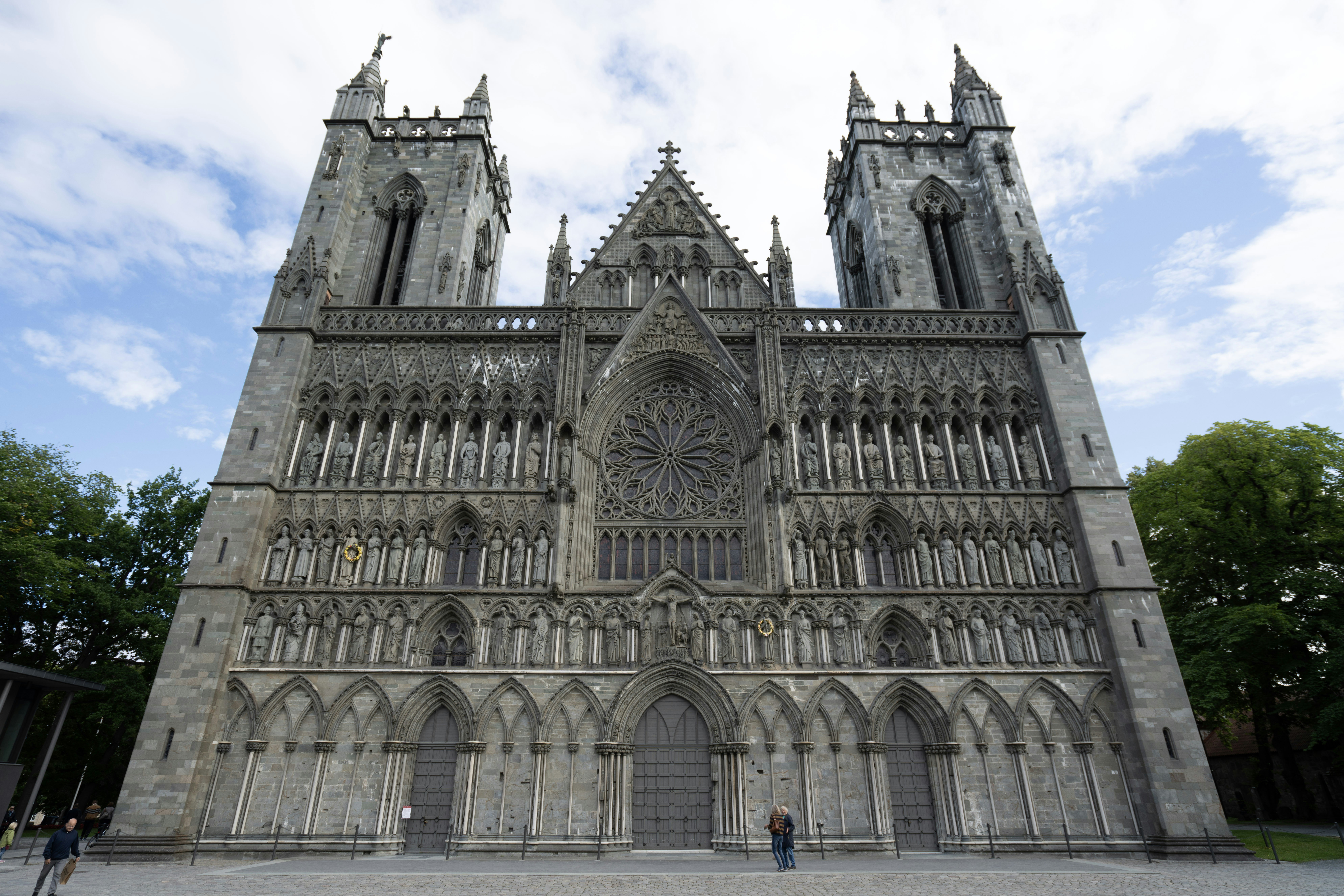 Nidaros Cathedral's intricate Gothic facade stands prominently under a cloudy sky in Trondheim.