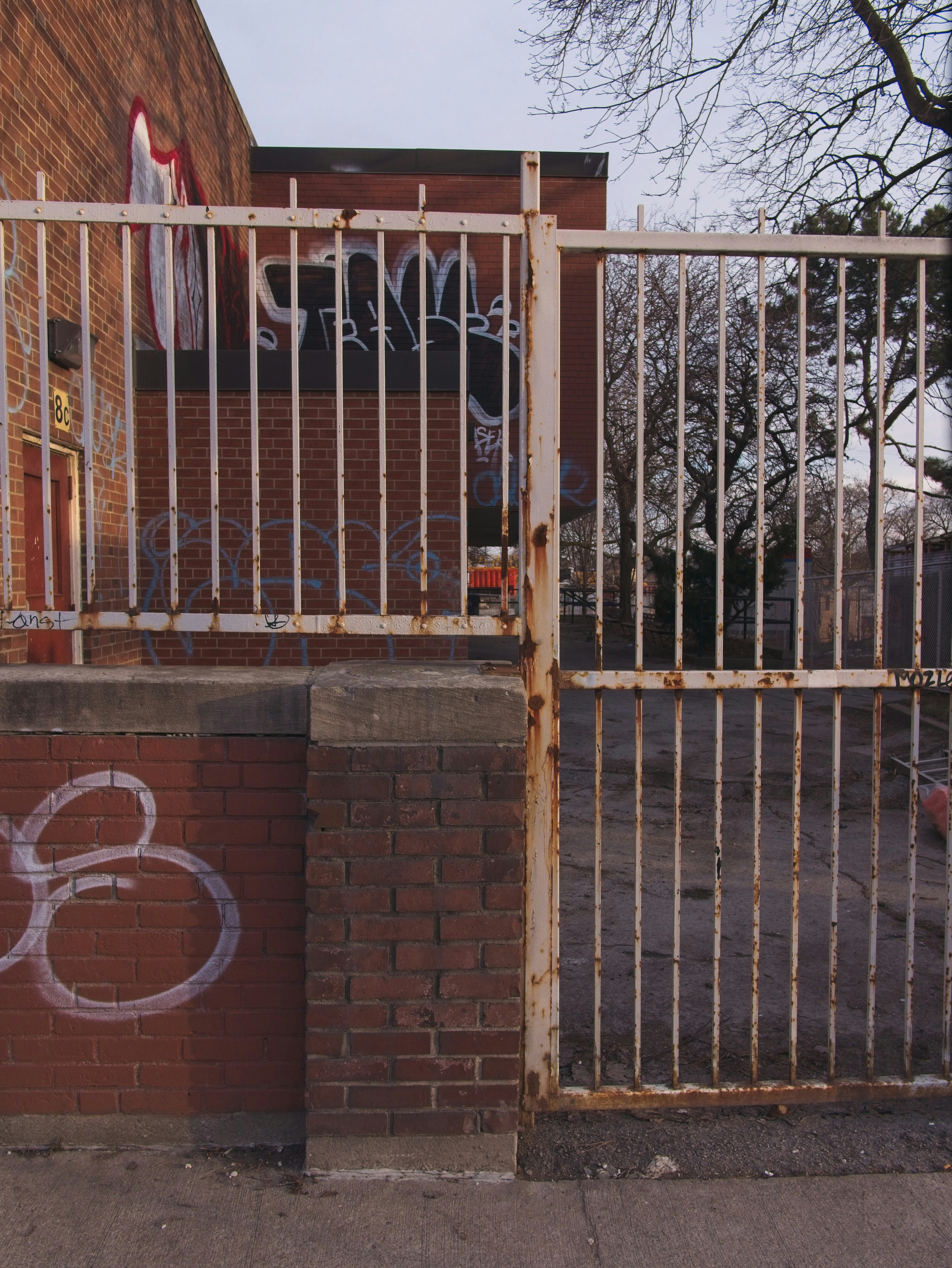 A brick building with a gate and graffiti on it photo – Free Toronto ...