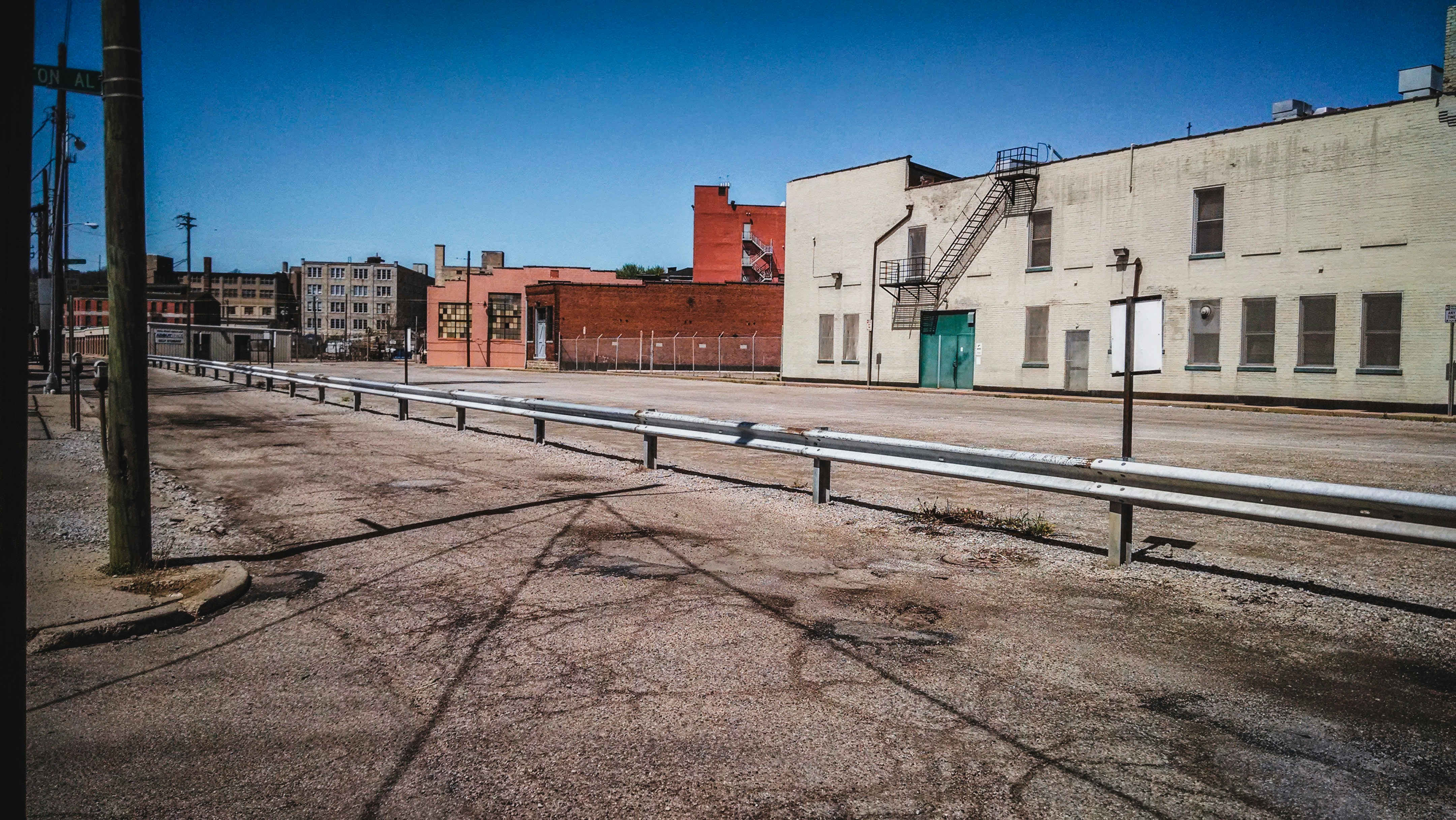 Deserted parking lot beside industrial buildings under a clear blue sky.
