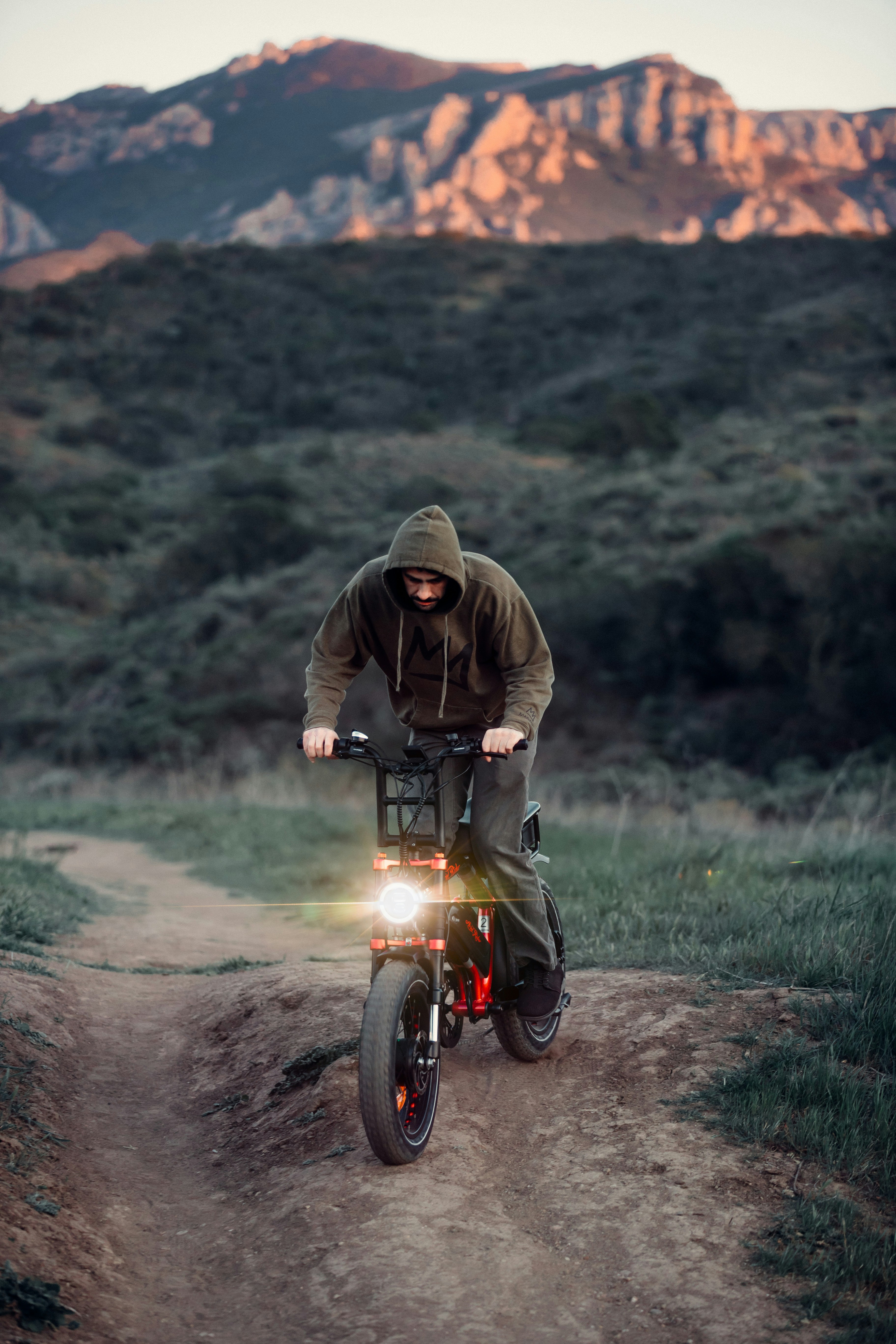 Male model riding ebike during golden hour sunset in the mountains.