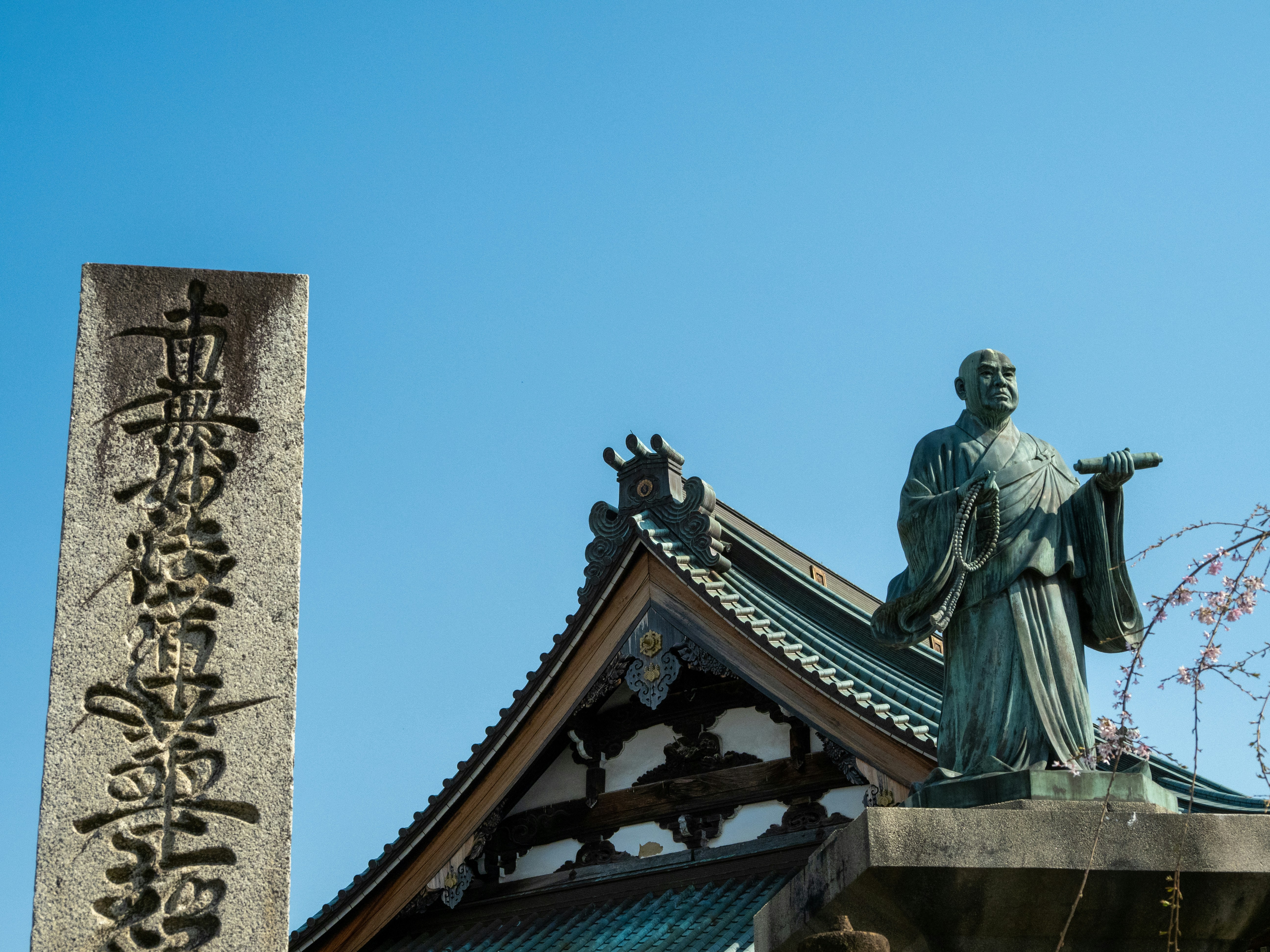 Bronze Monk Statue at a Japanese Temple Courtyard Under a Clear Blue Sky