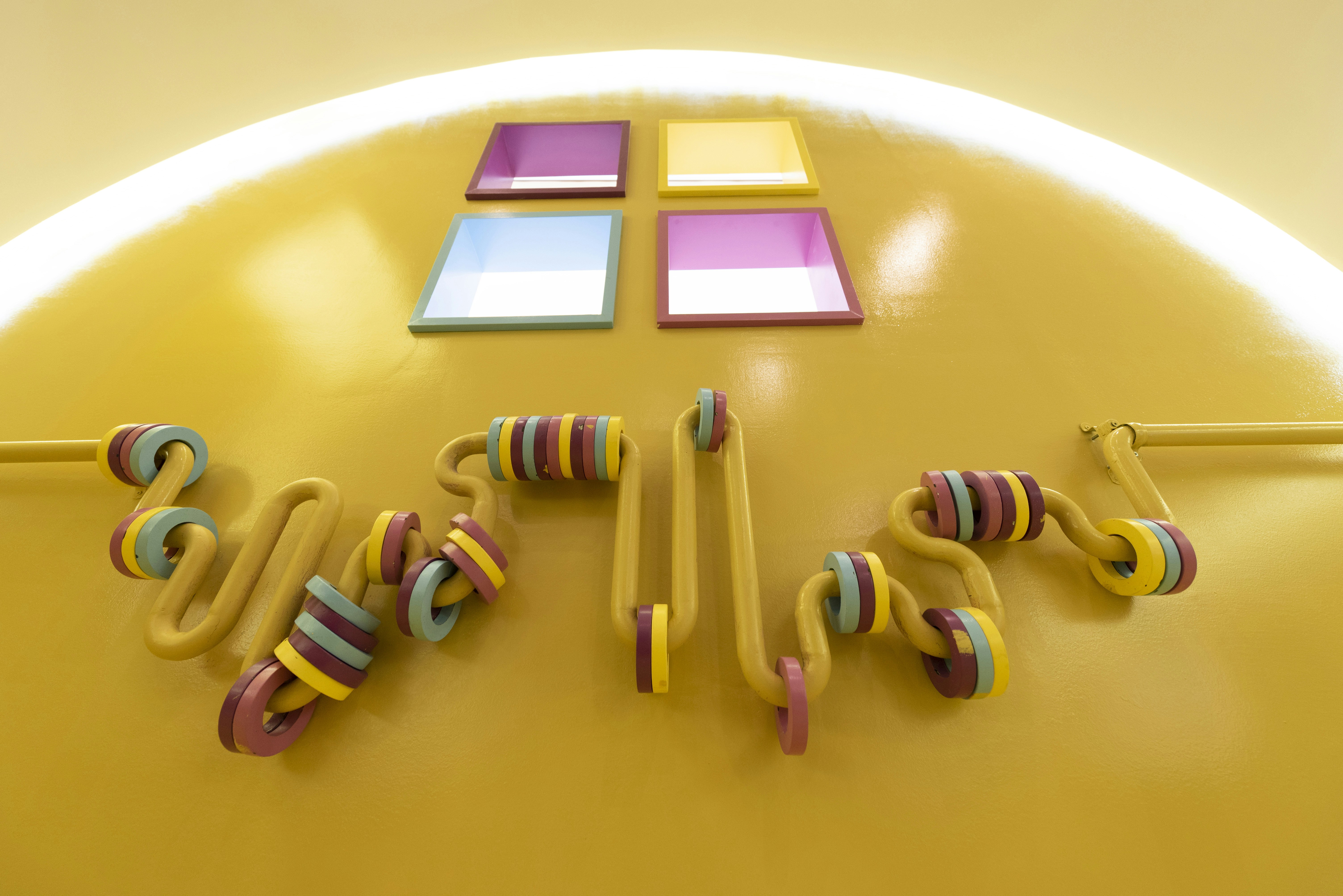Bright Yellow Wall with Playful Colored Tubes and Rectangles