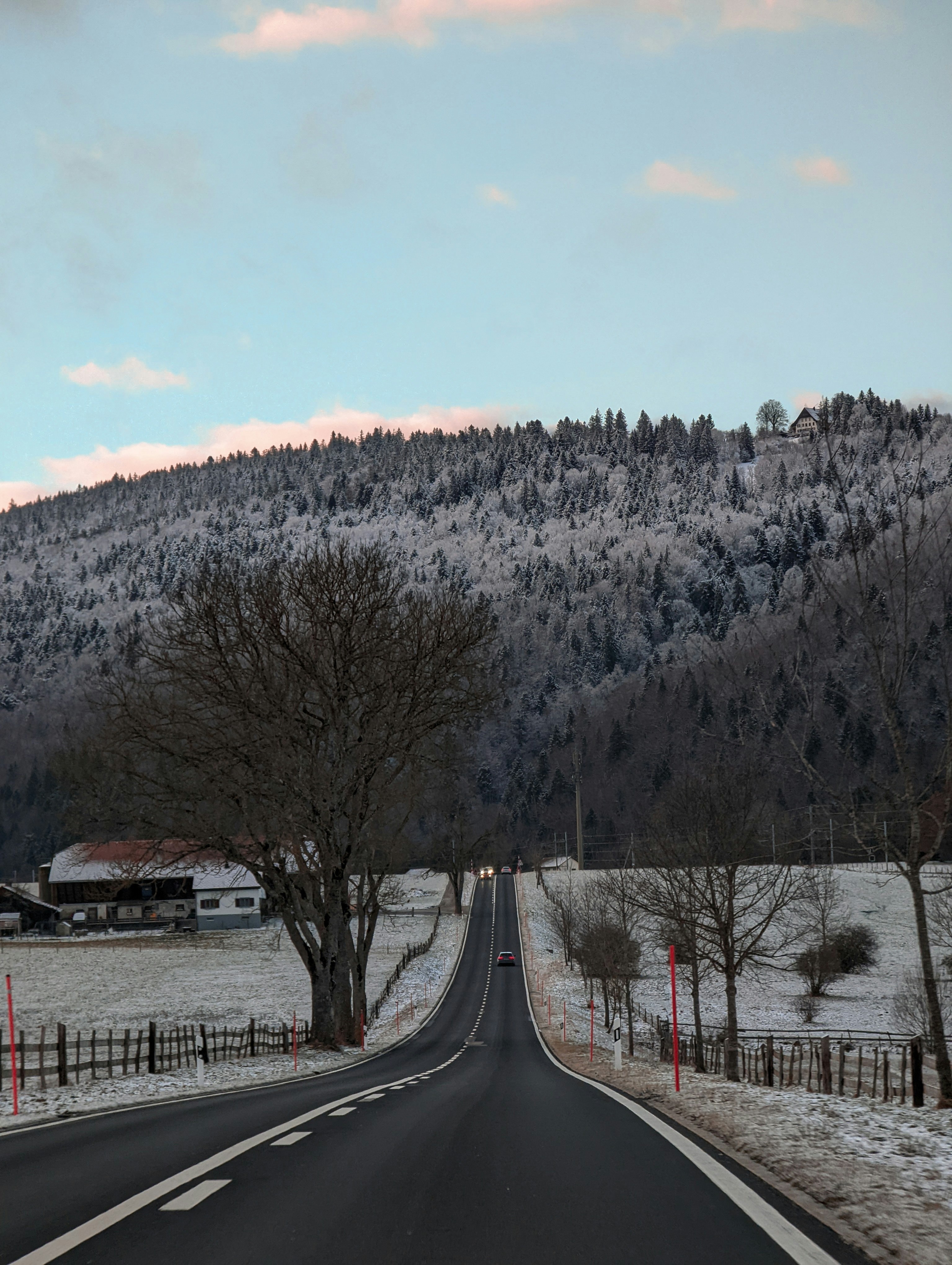 a rural road with a snow covered mountain in the background