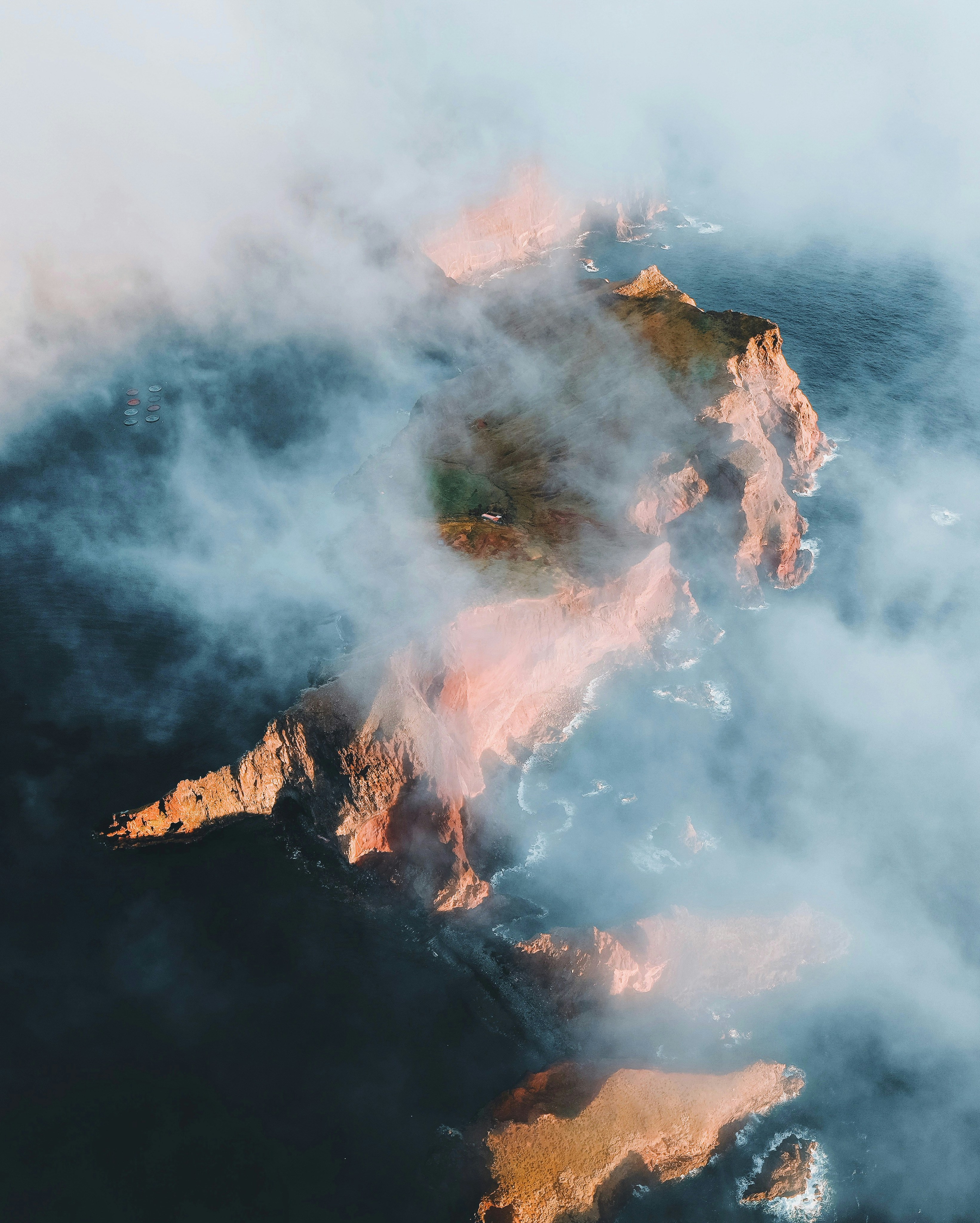 Sunlit Cliffs Pierced by Sea Mist: An Aerial Portrait of a Coastal Promontory