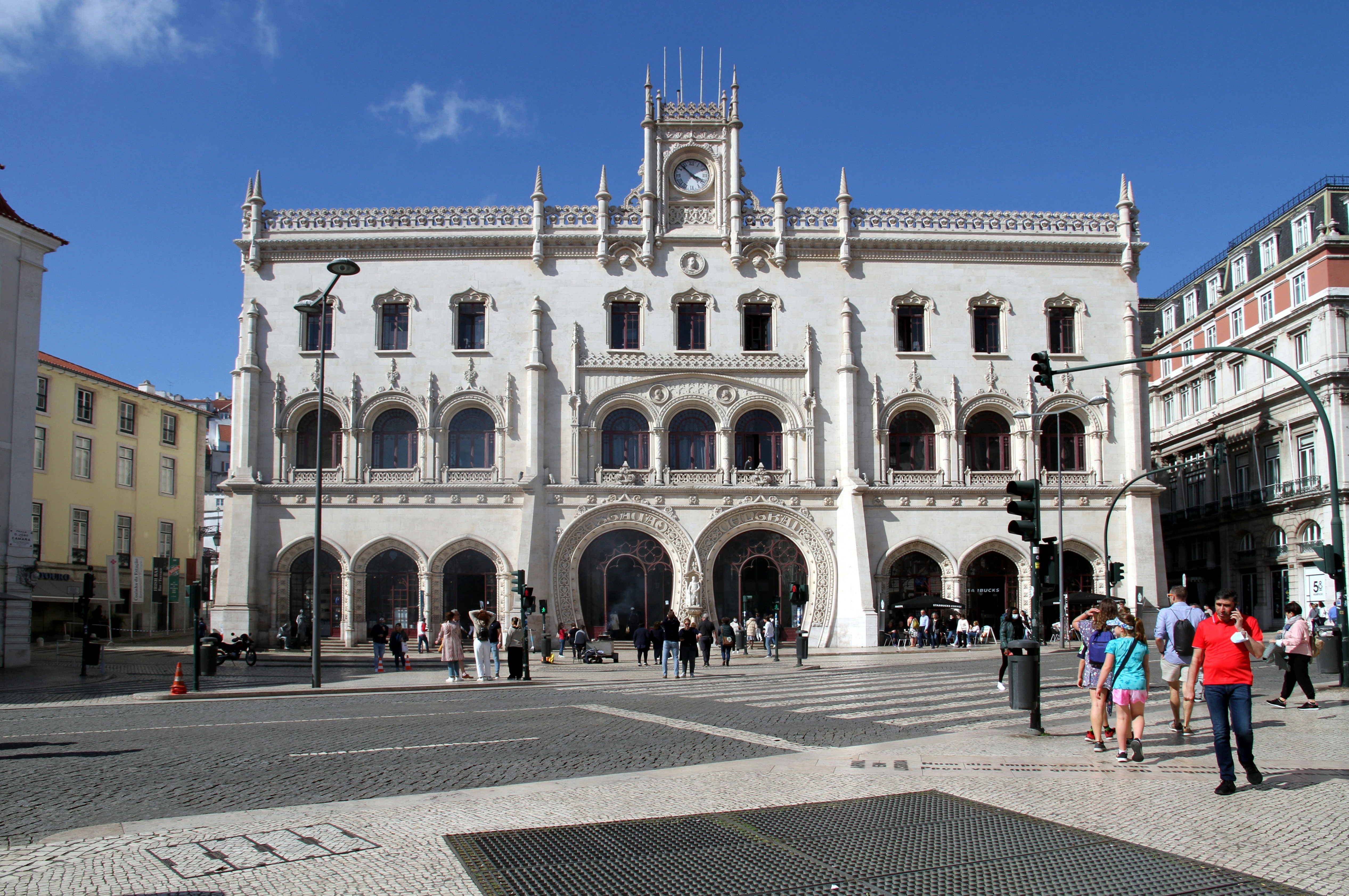 Grand historic building in Lisbon featuring ornate architecture and bustling pedestrian activity in the foreground.
