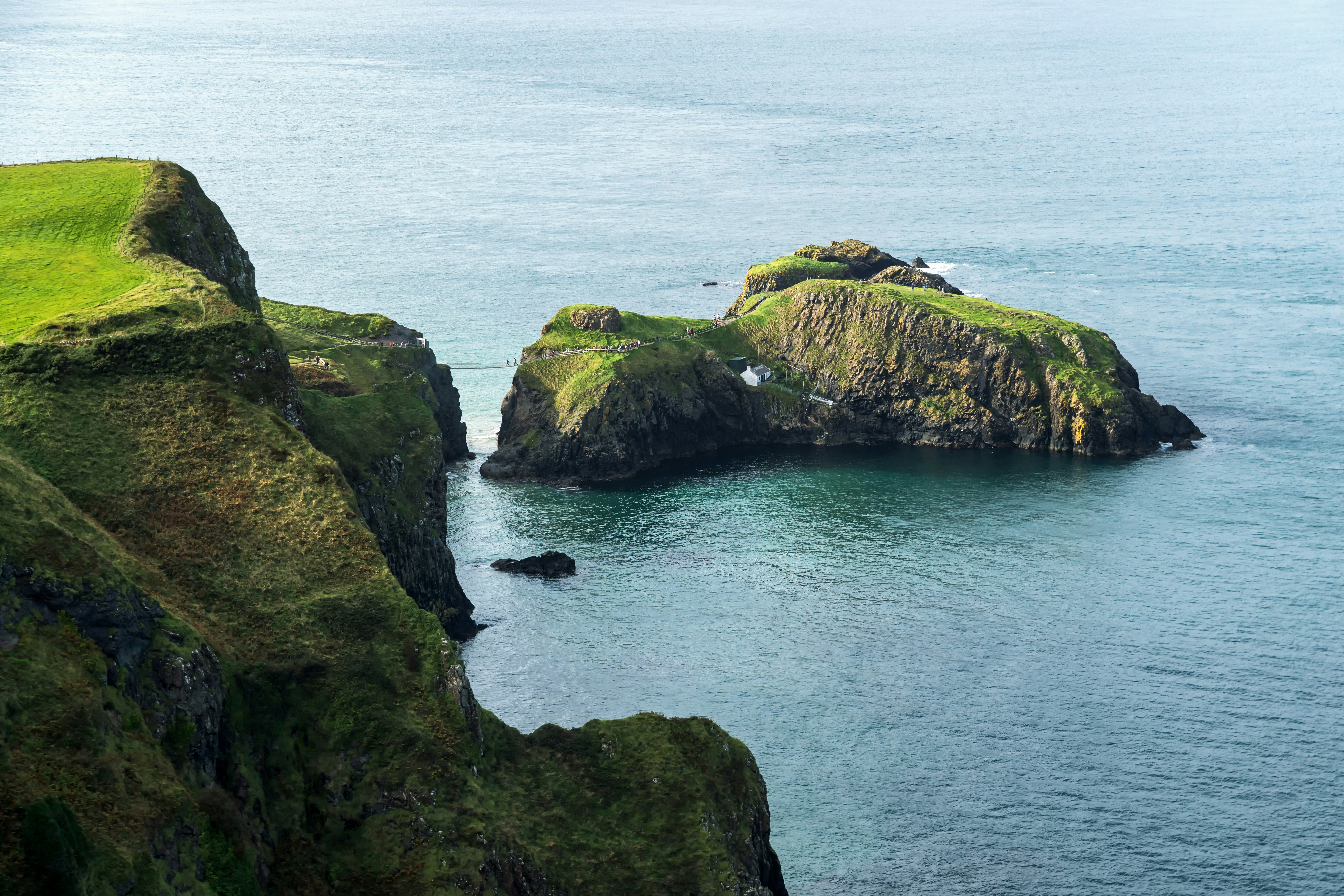 Rope Bridge, Ballycastle | a large body of water next to a lush green hillside