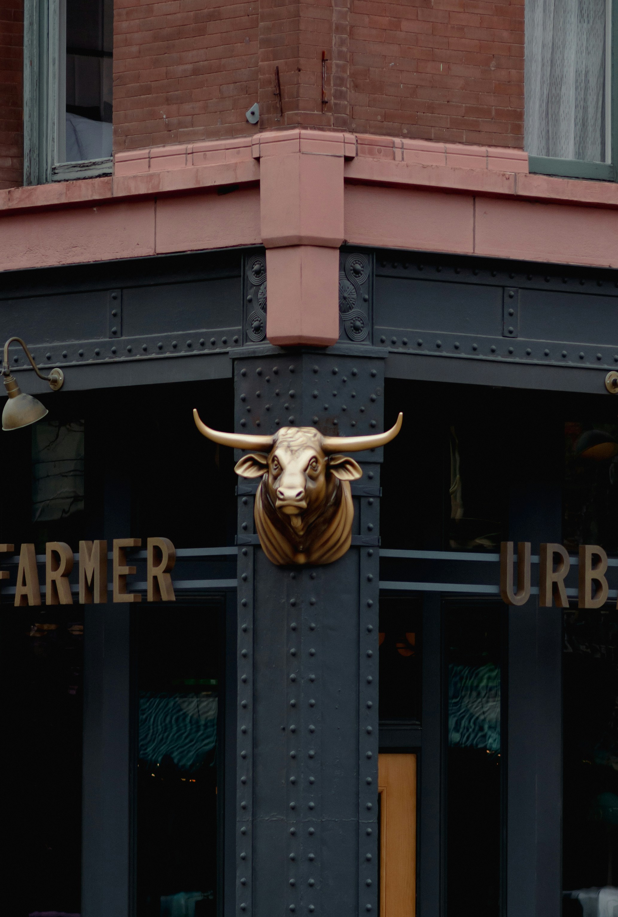 Golden Bull Head on a Riveted Pillar Guarding Urban Market Façade