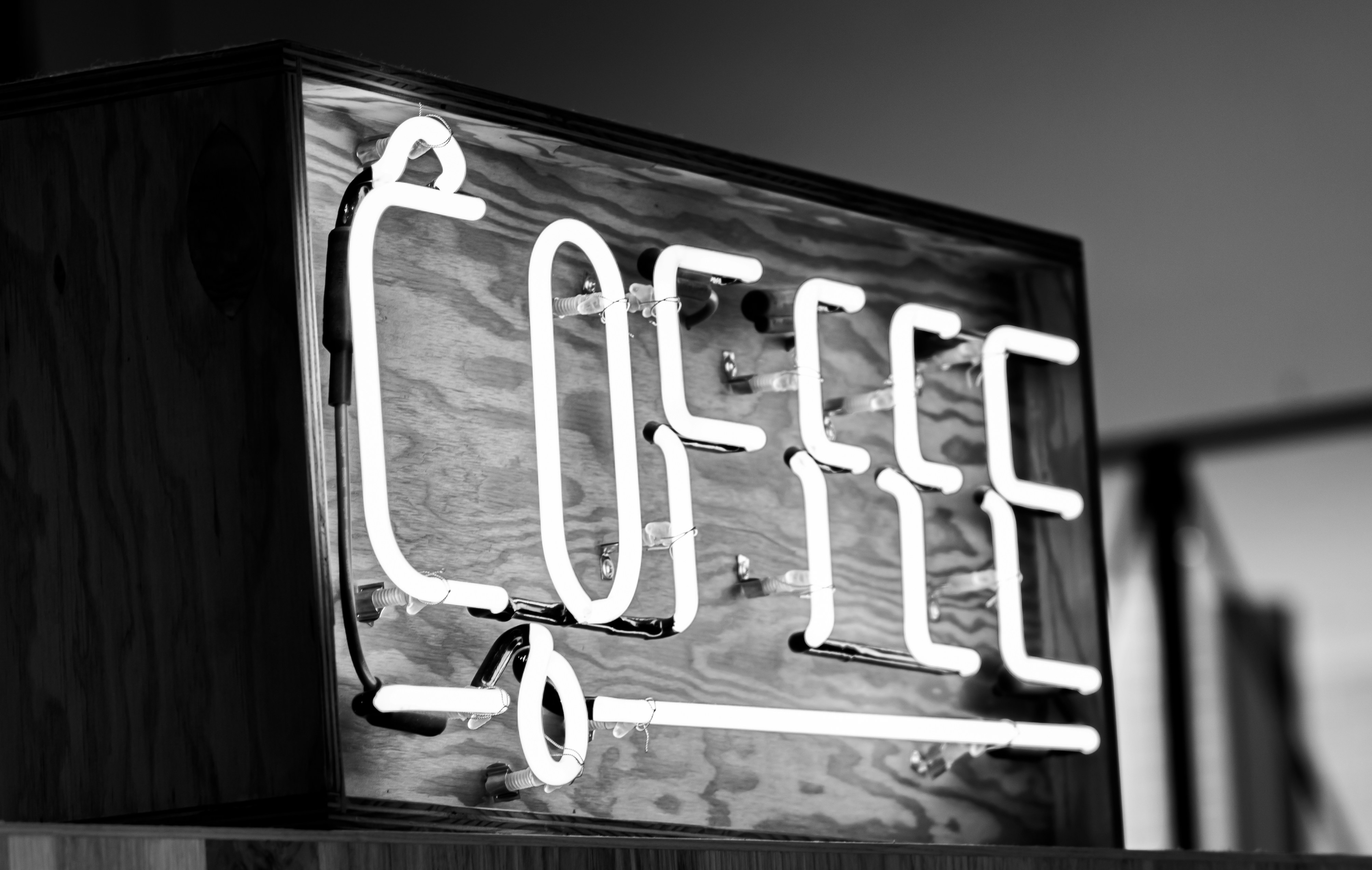Black and white neon sign displaying the word 'coffee' with a rustic wooden background.