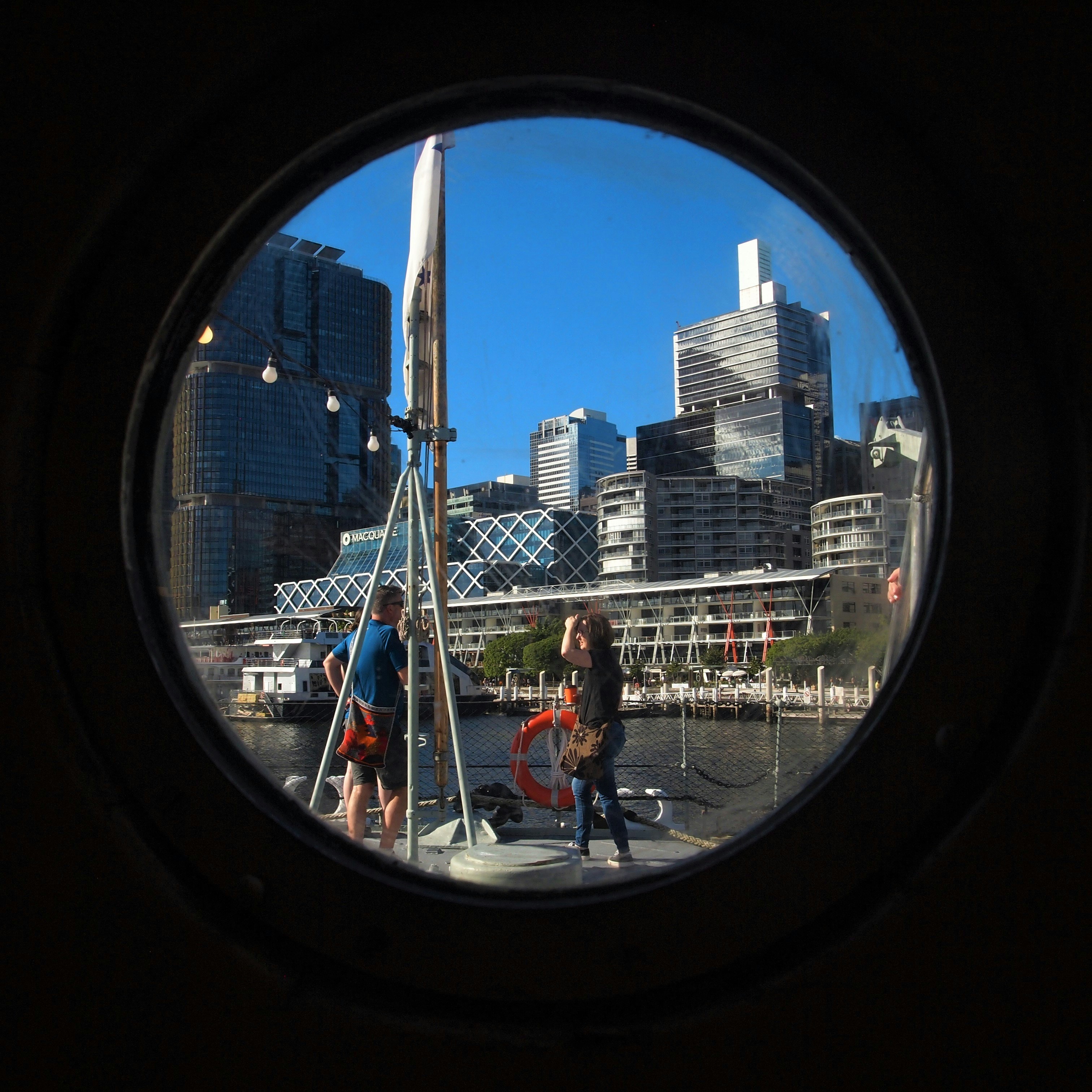 Porthole Perspective: Dockside Portraits Before a Glassy City Skyline
