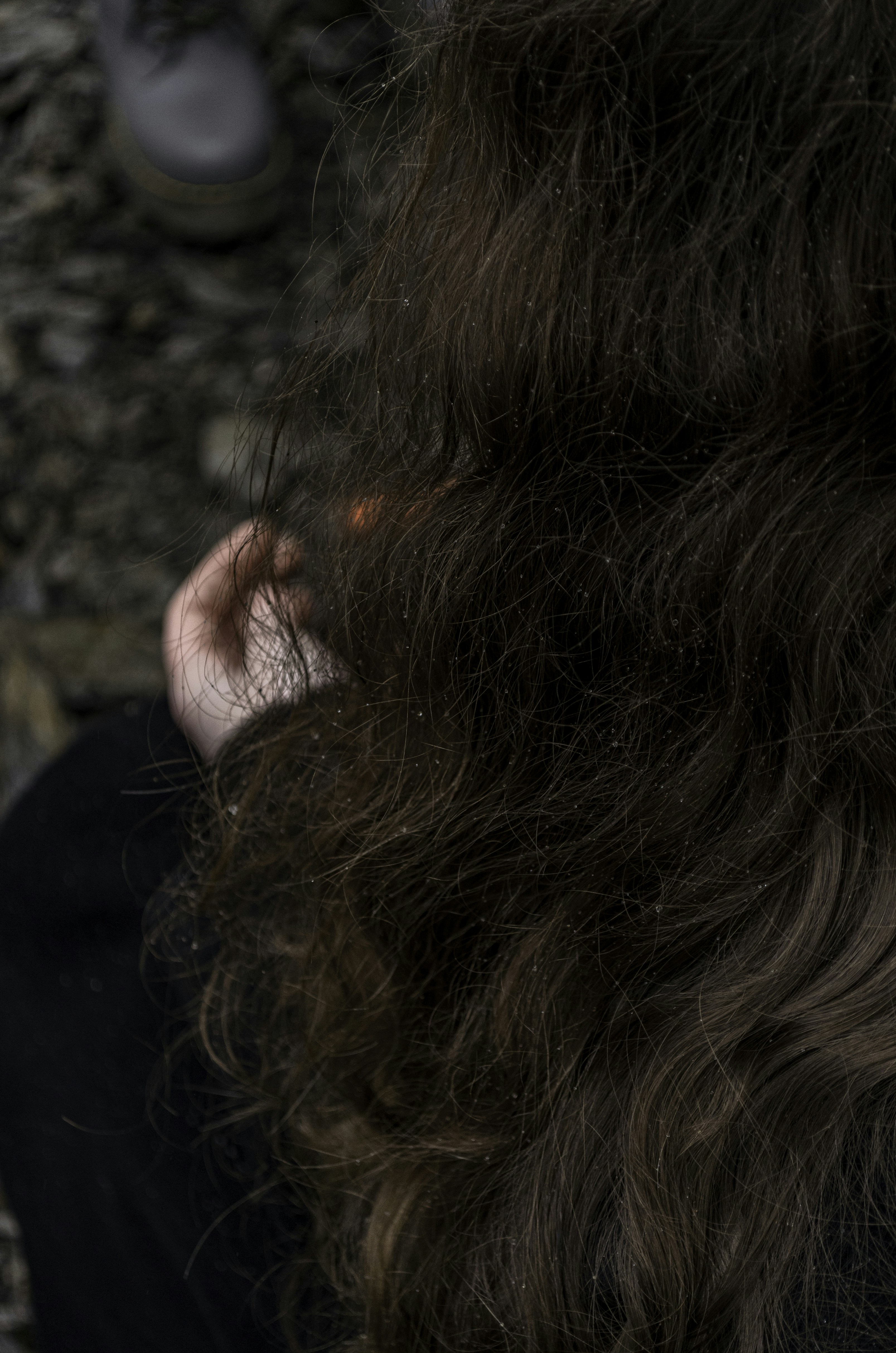 Behind-the-head portrait: tangled chestnut curls frame a quiet moment