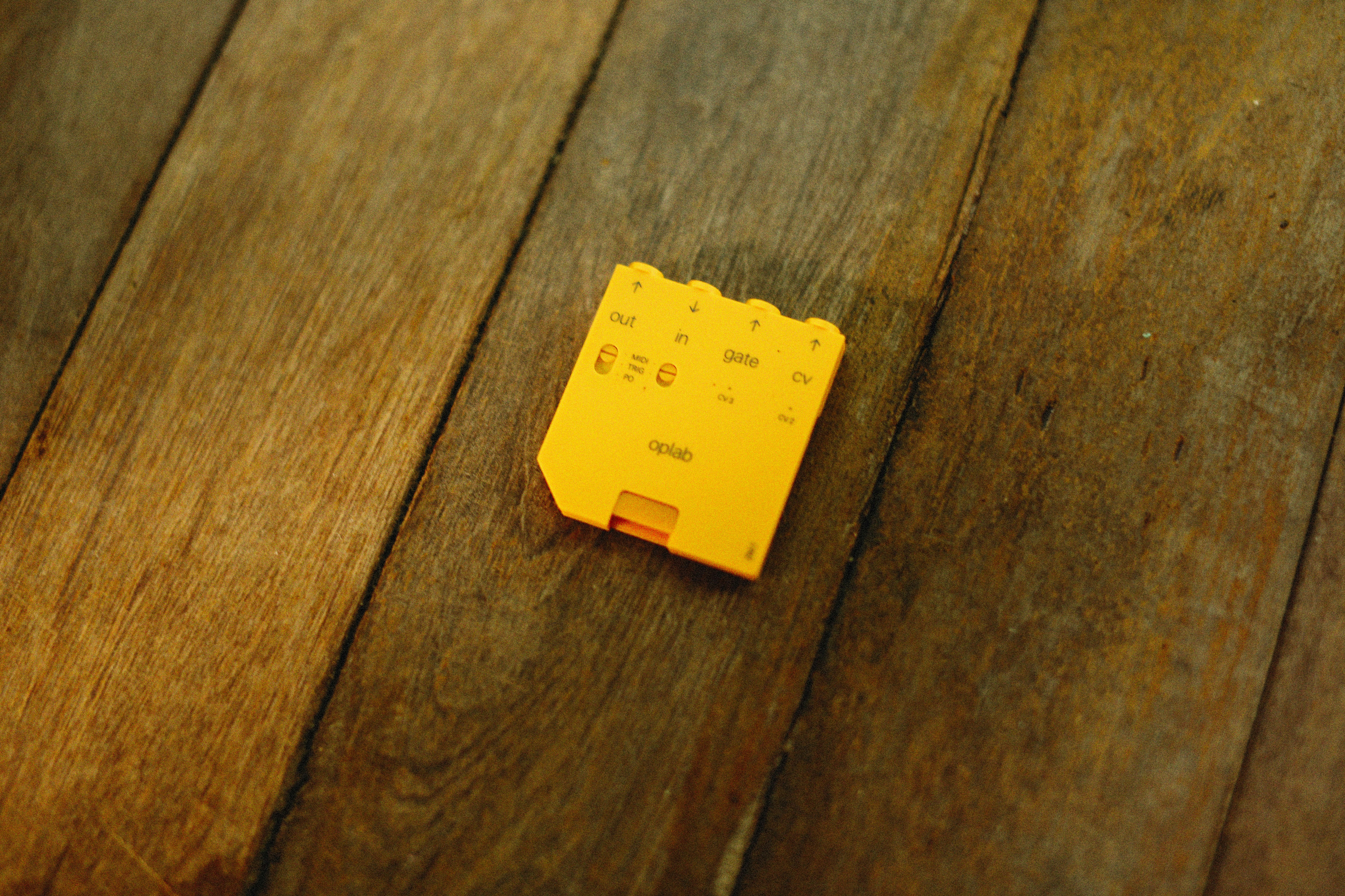 Bright yellow tool resting on a rustic wooden surface, showcasing its functional design and texture contrast.
