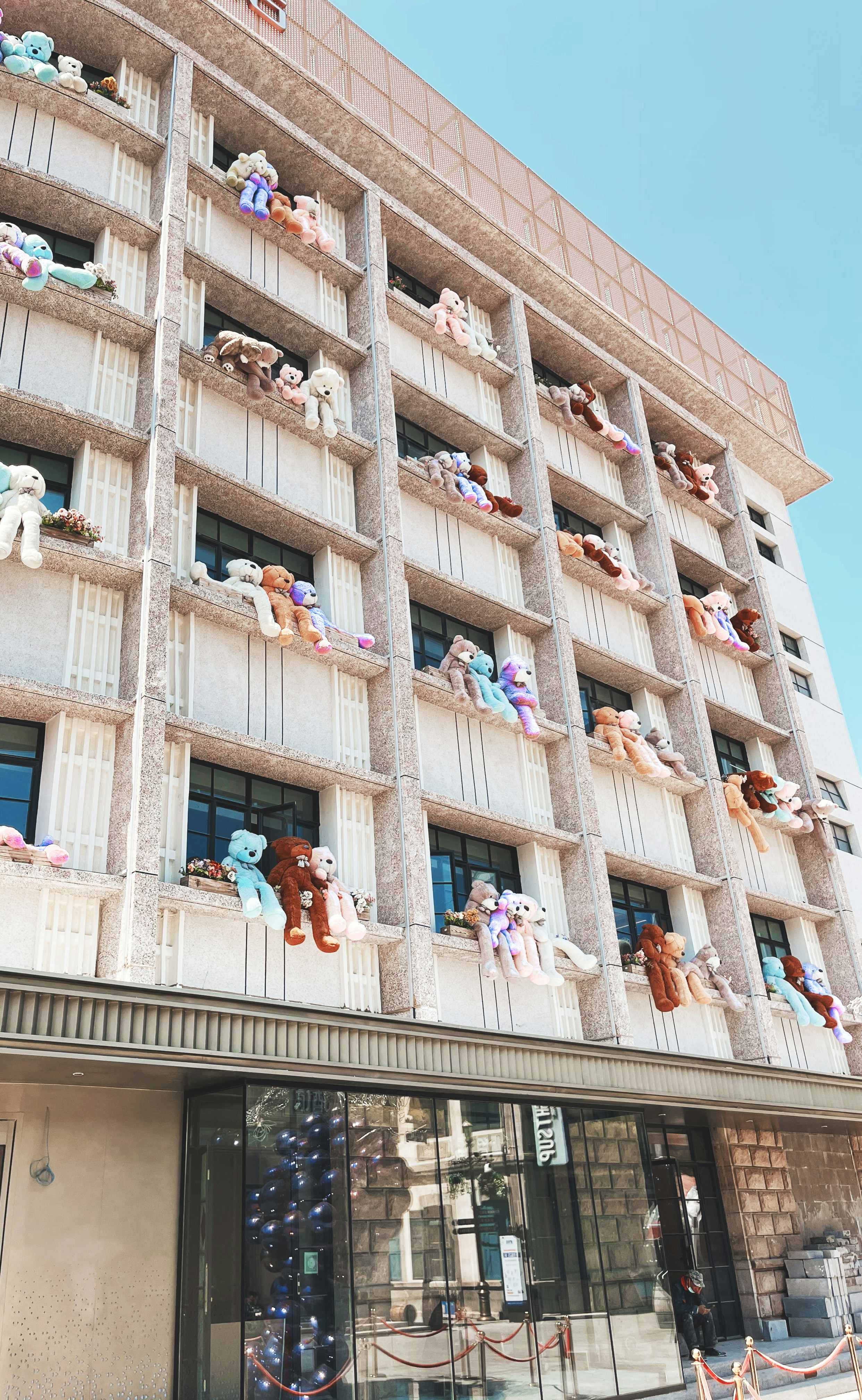 A tall building with a bunch of stuffed animals on the windows photo ...