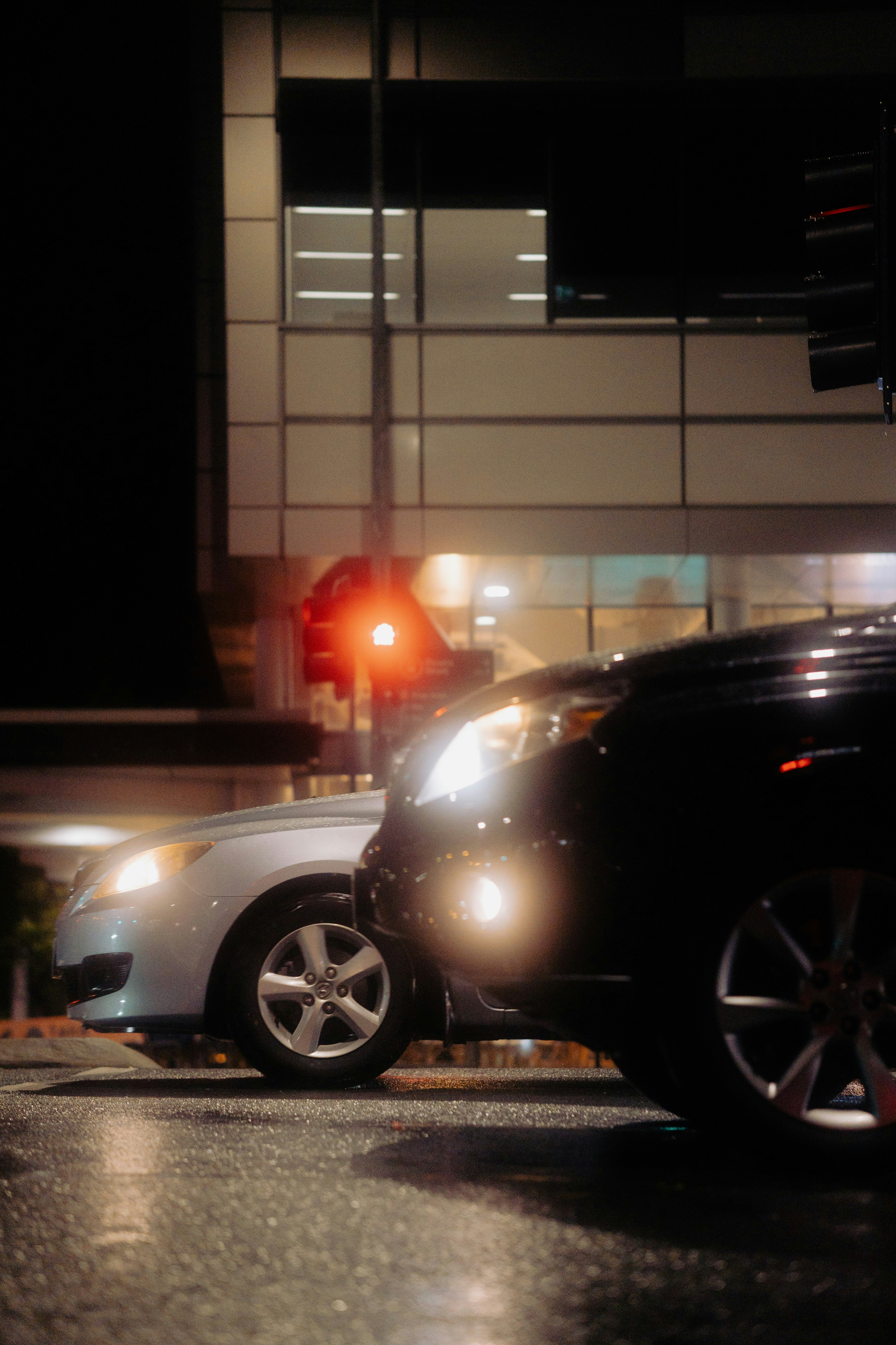 Red Light Convergence: Nighttime Intersection Between White and Black Sedans