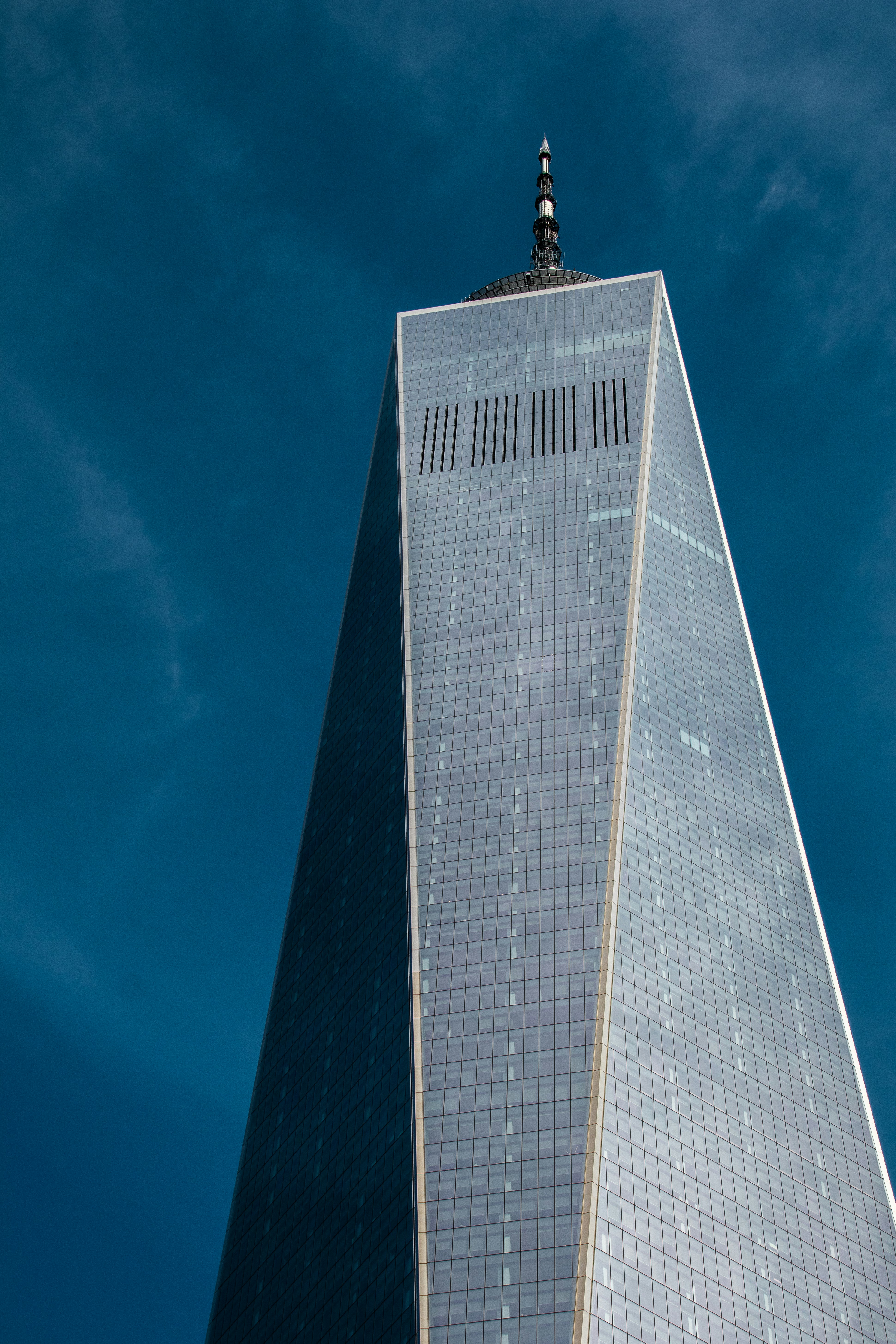 A towering skyscraper pierces the sky, showcasing its sleek glass façade against a vibrant blue background.