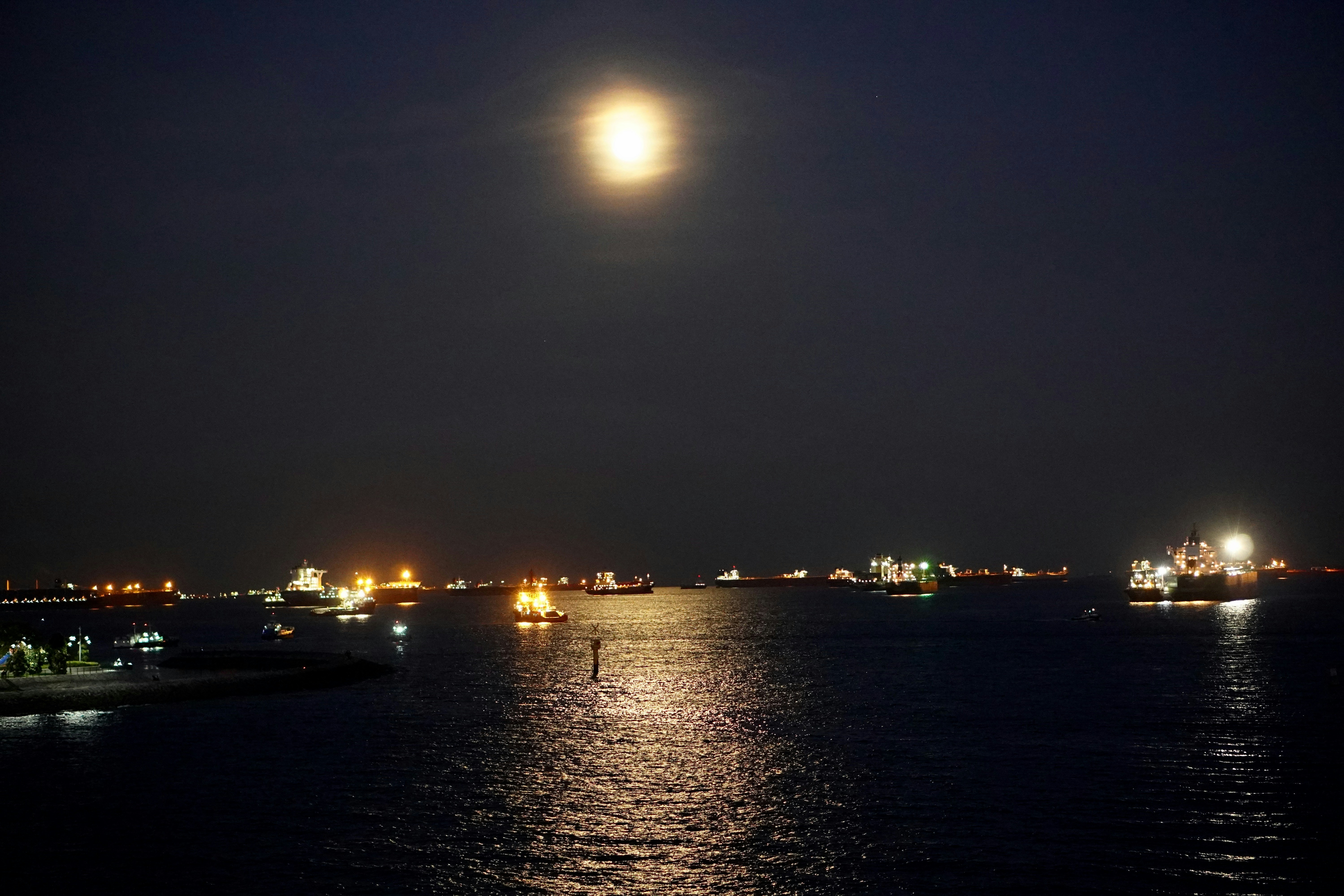 a full moon is seen over the water at night