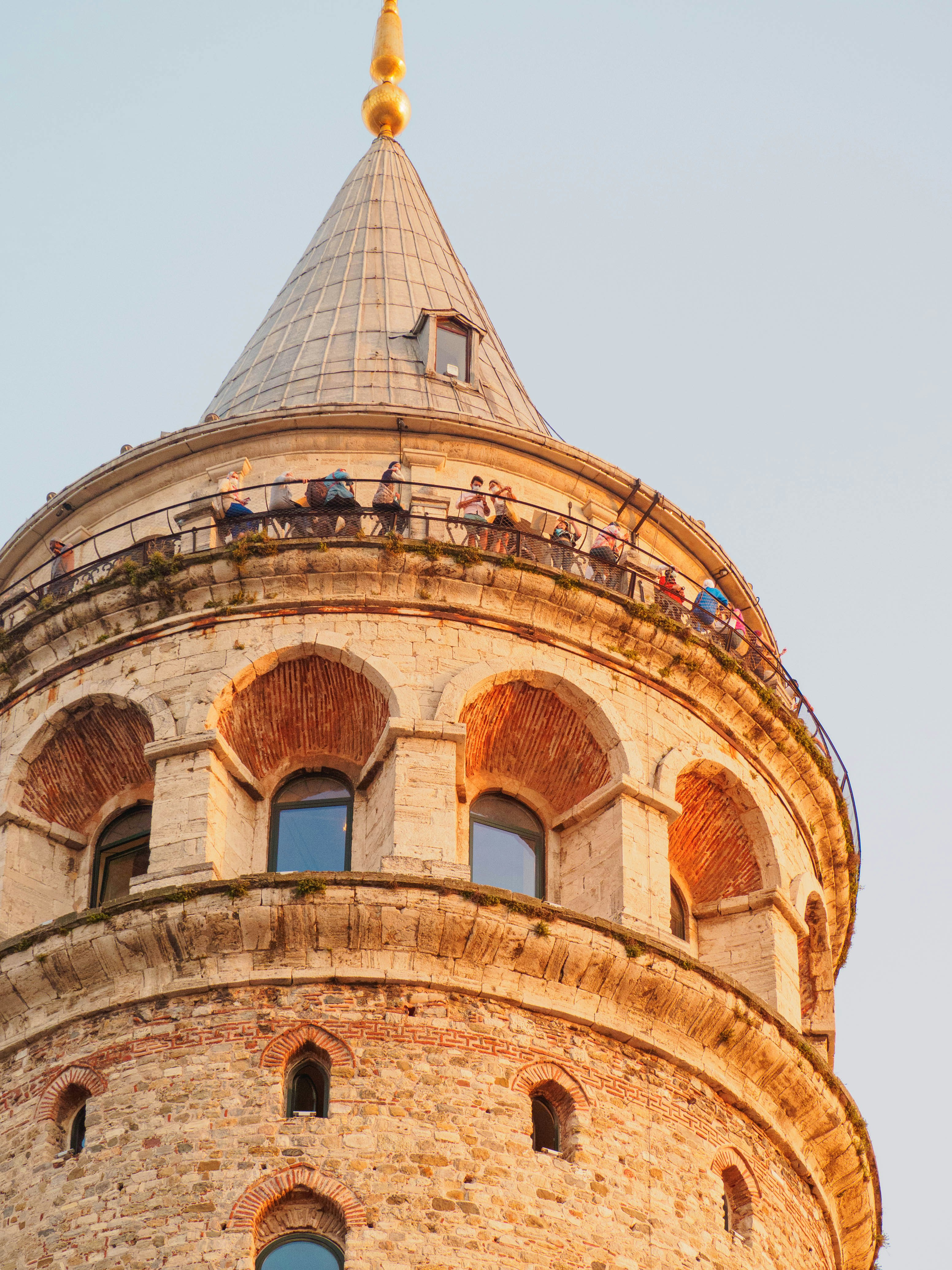 Golden Hour Circles: Tourists Crowding a Historic Turret Balcony