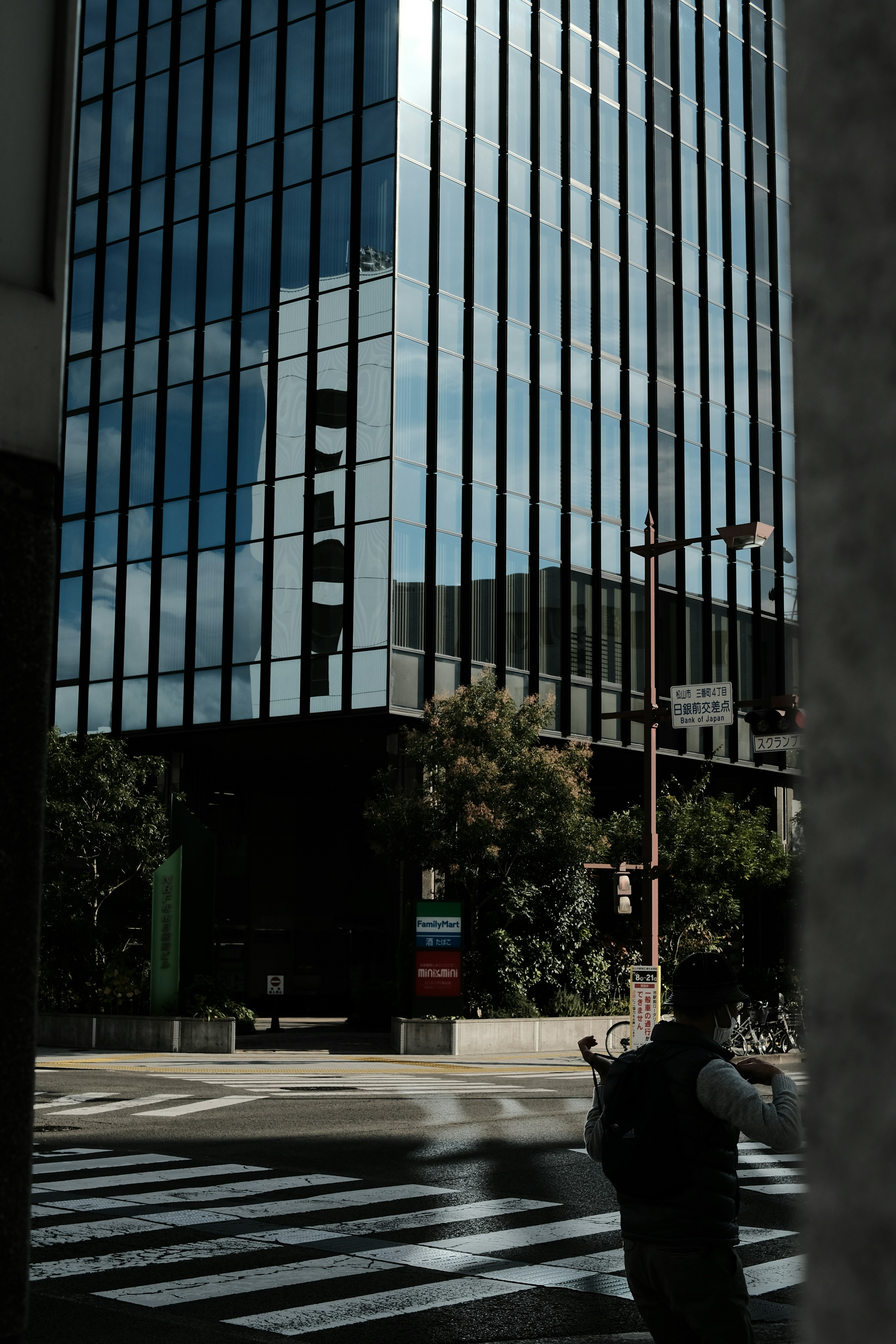 A man is crossing the street in front of a tall building photo – Free ...