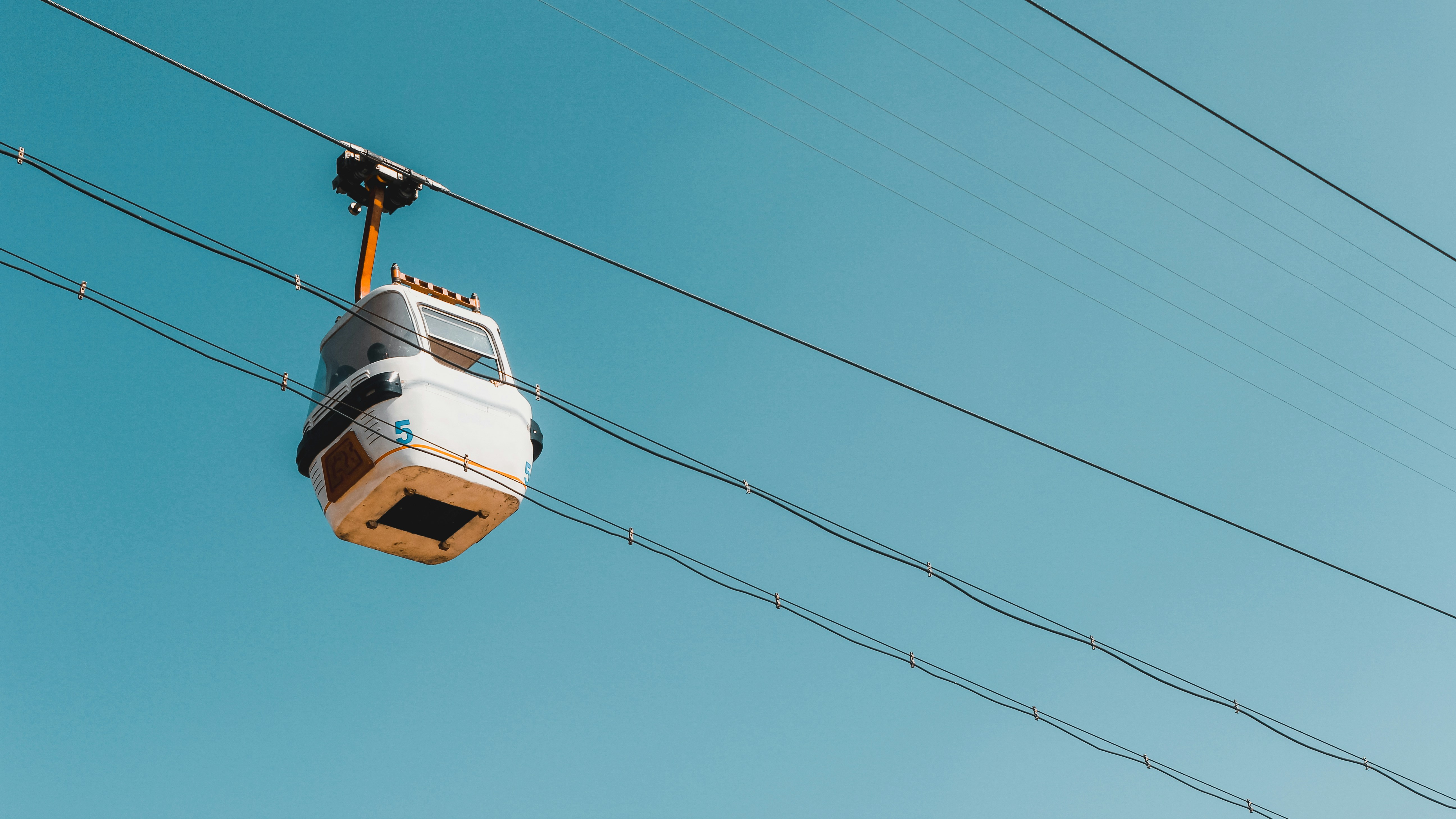 A gondola glides through a clear blue sky, suspended on cables, evoking a sense of adventure and exploration.