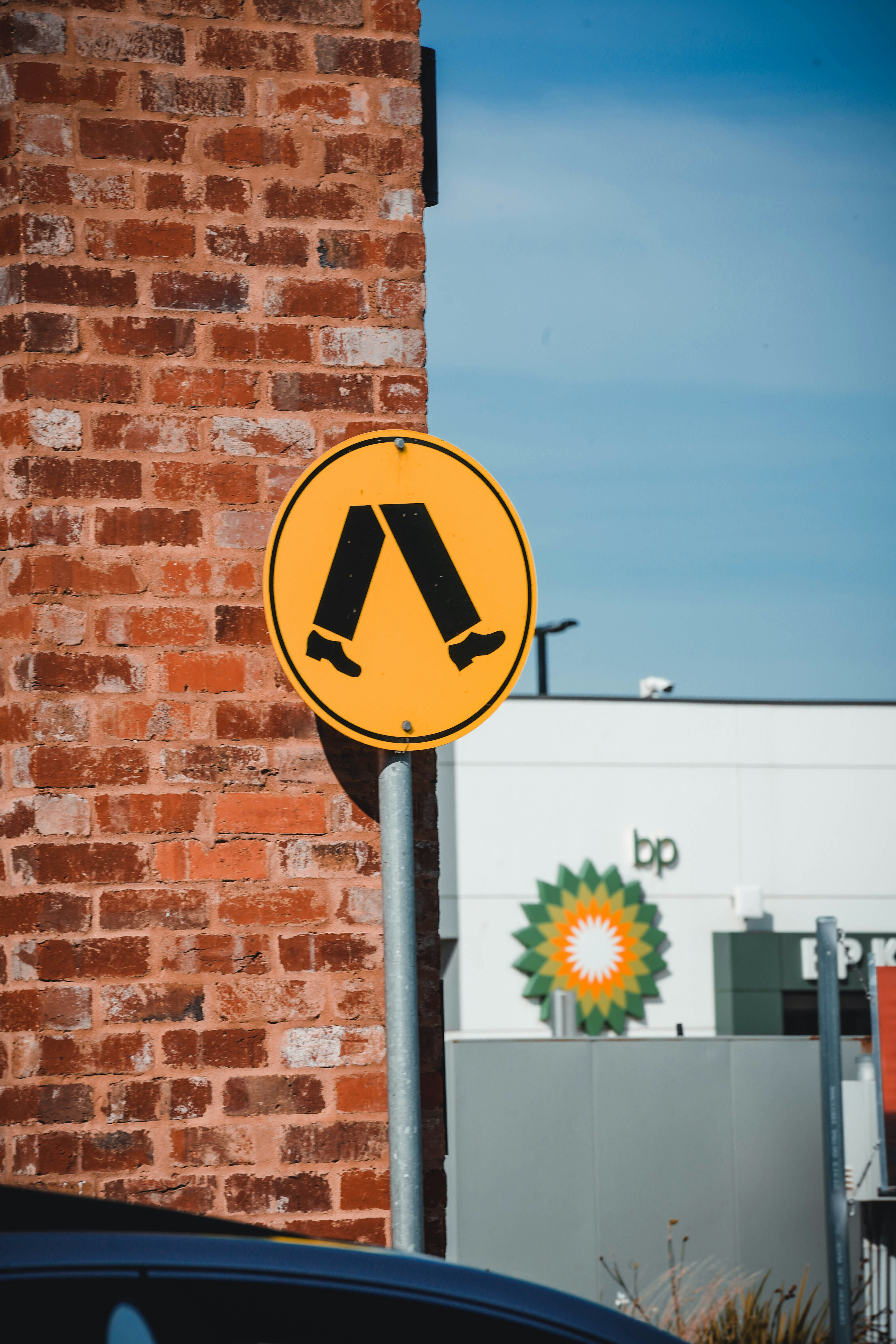 A yellow and black street sign next to a brick building photo – Free ...