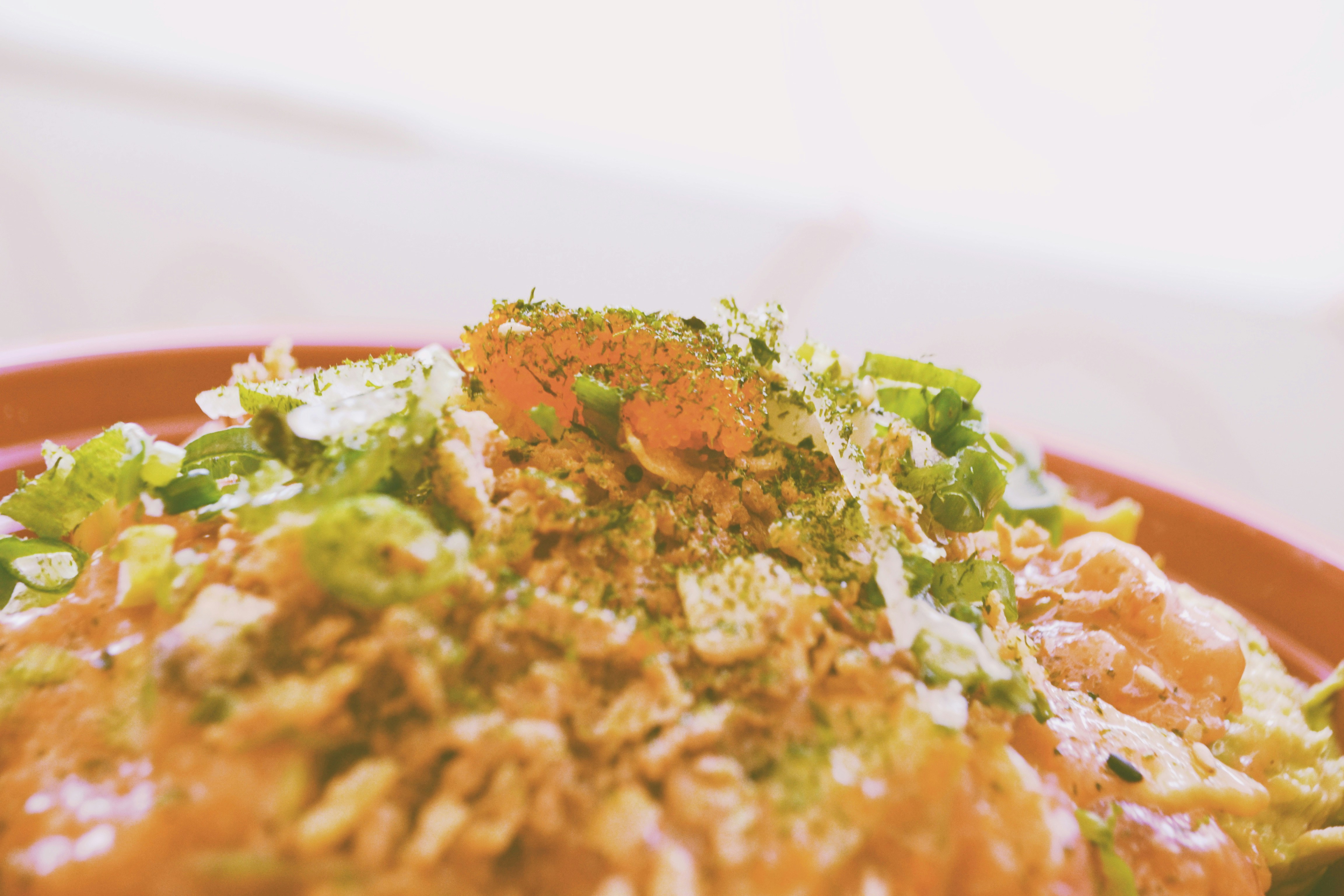 Close-up of a vibrant dish topped with green onions and spices, showcasing a rich texture and color palette.