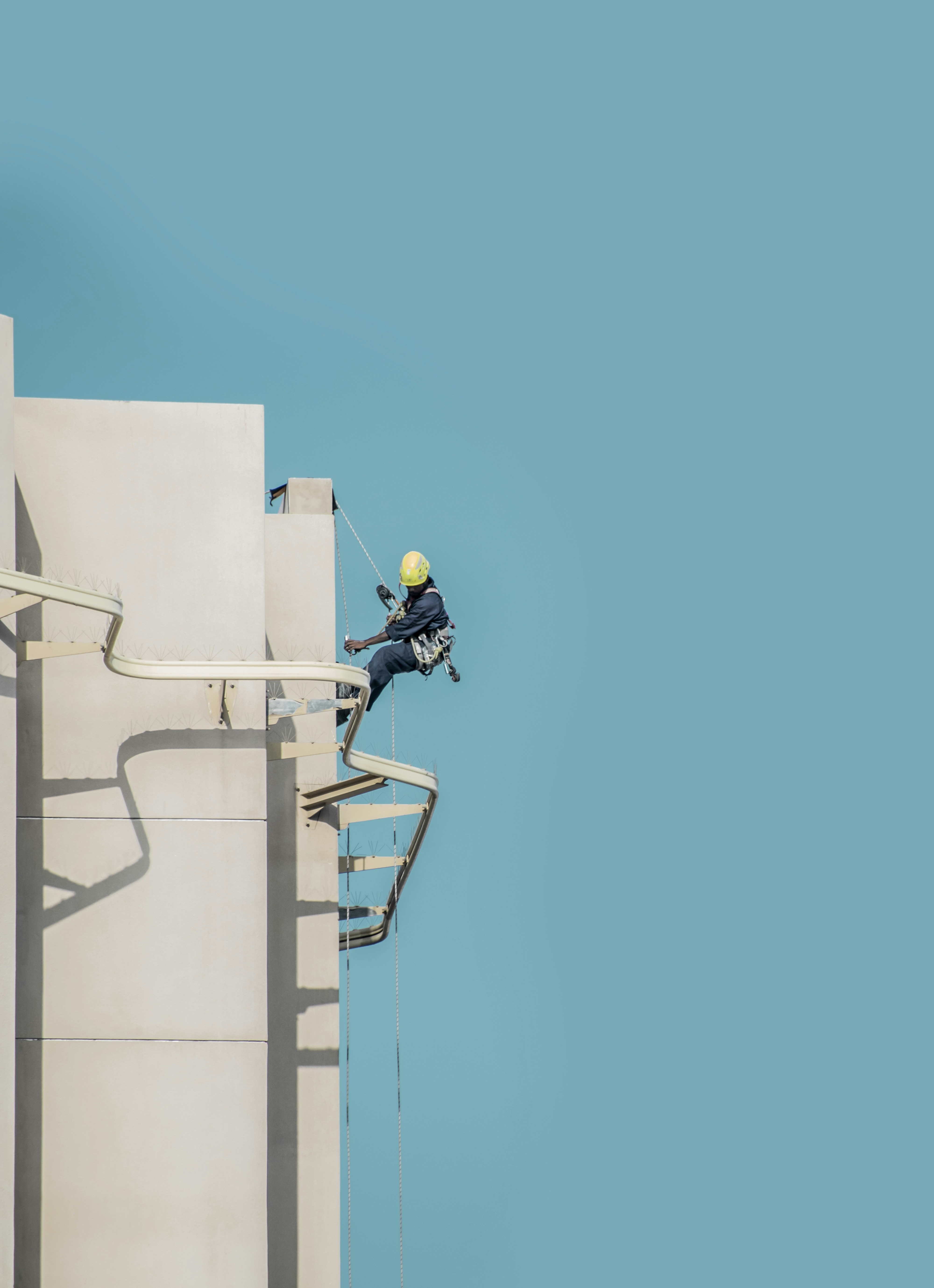 A man climbing up the side of a tall building photo – Free Dubai ...