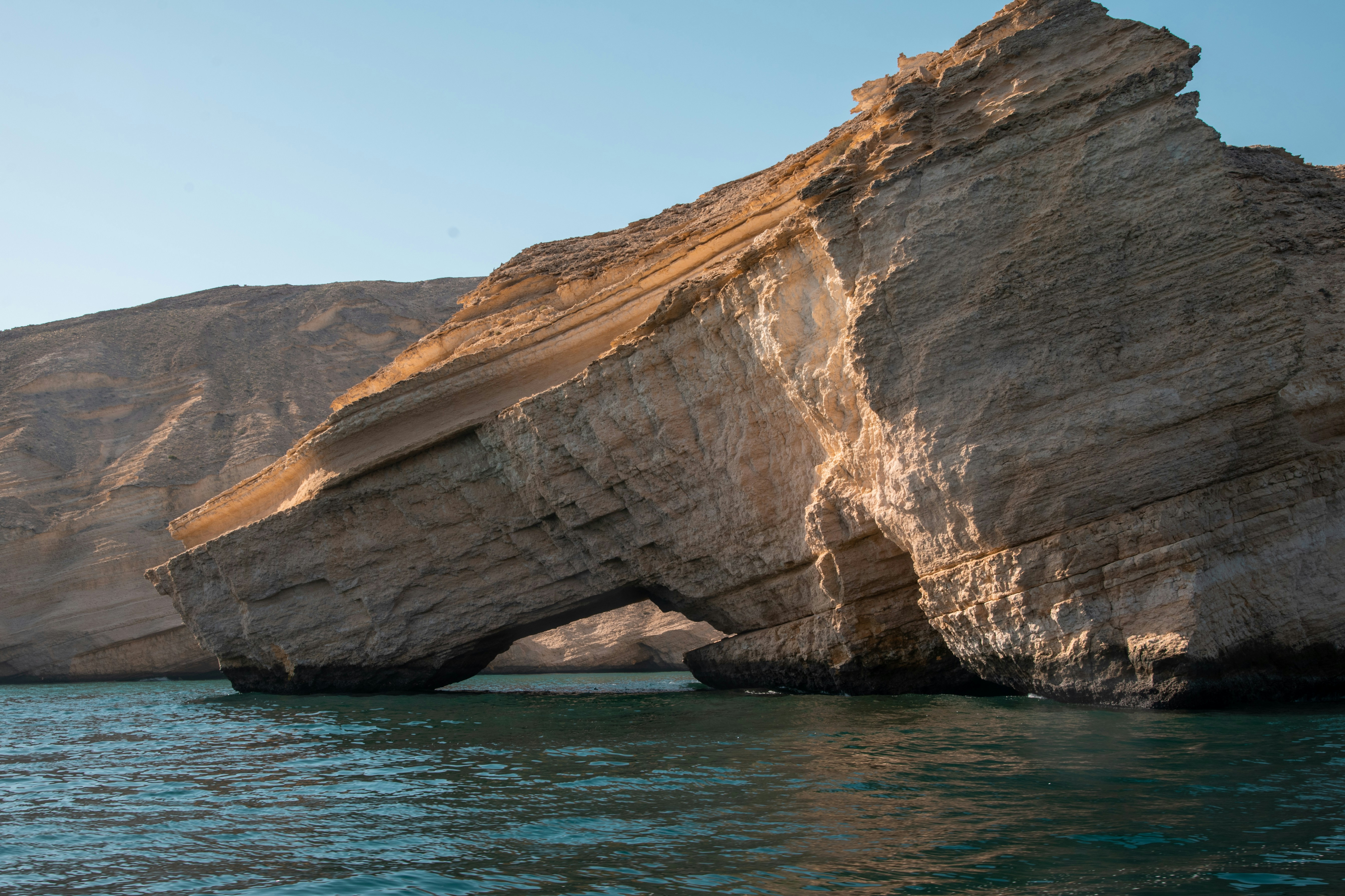 A large rock formation in the middle of a body of water photo – Free ...